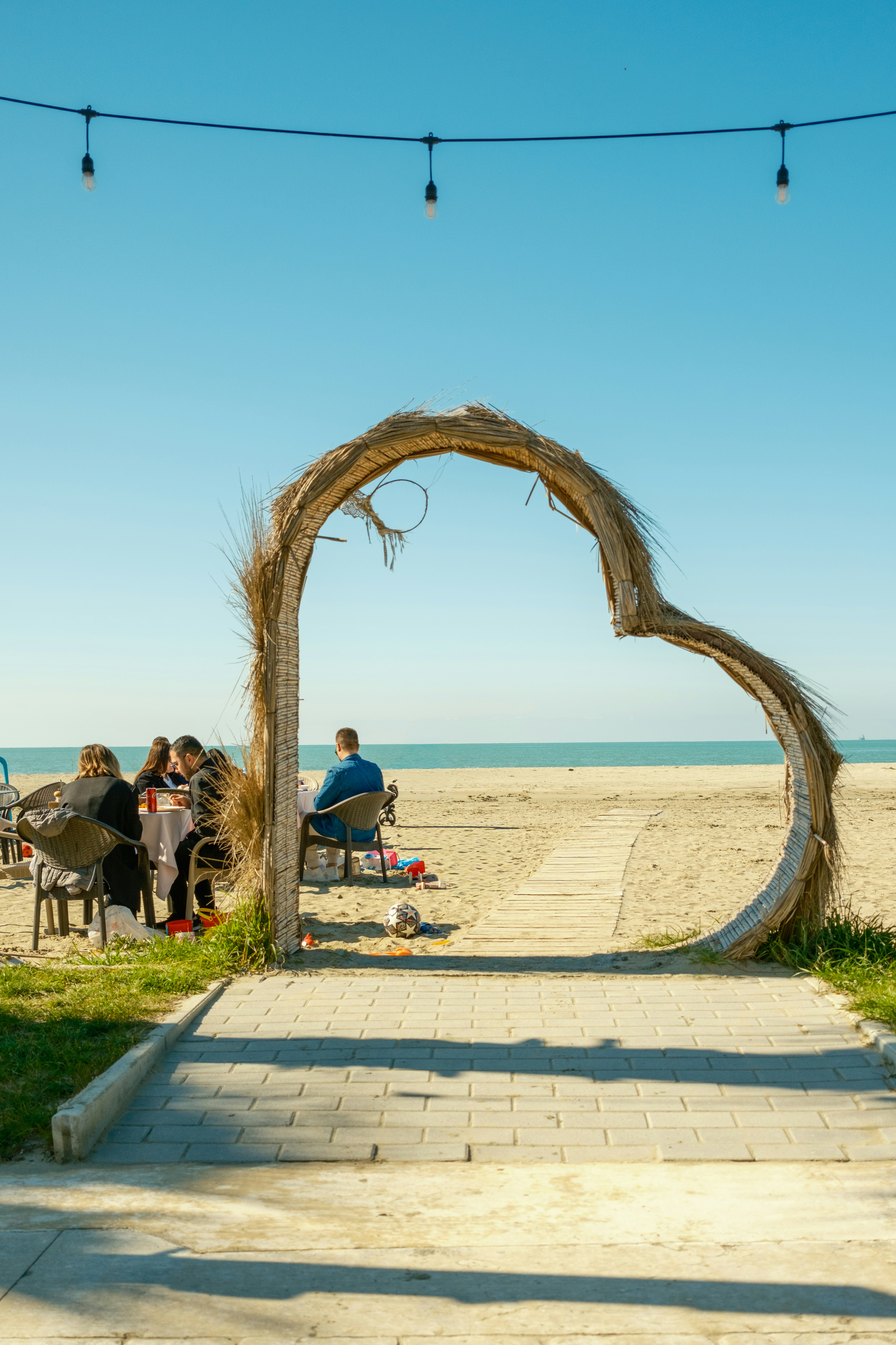 Circular Arch on the Beach: Evening Guests Under Blue Sky