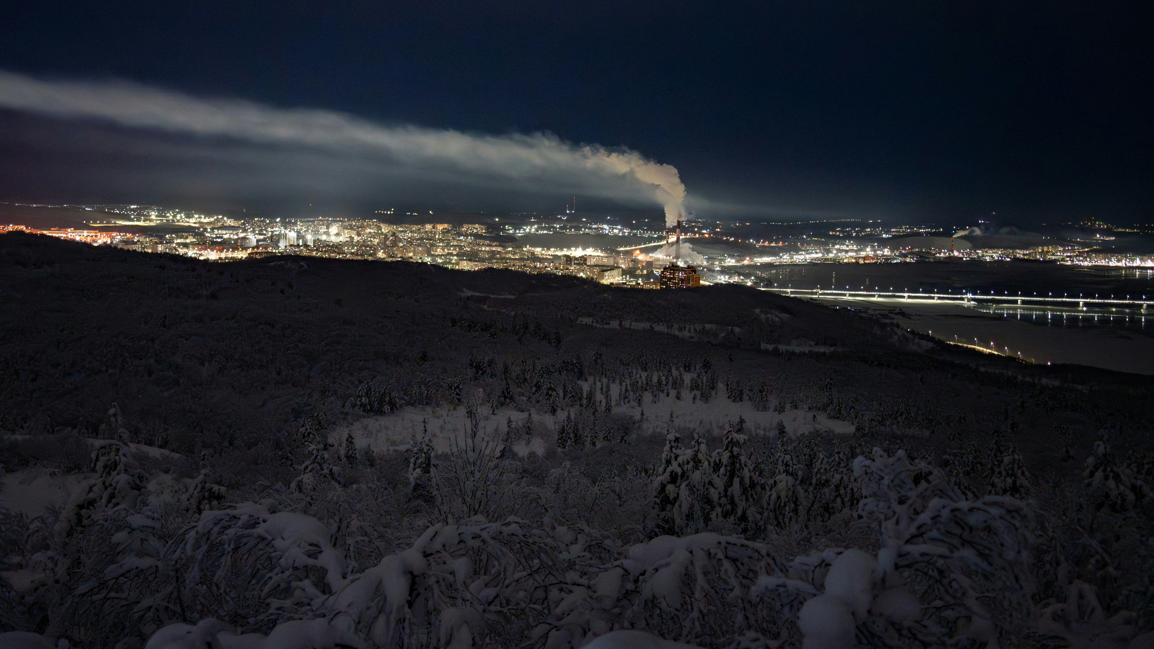 Nighttime Industrial Glow Over Snow-Covered Hills
