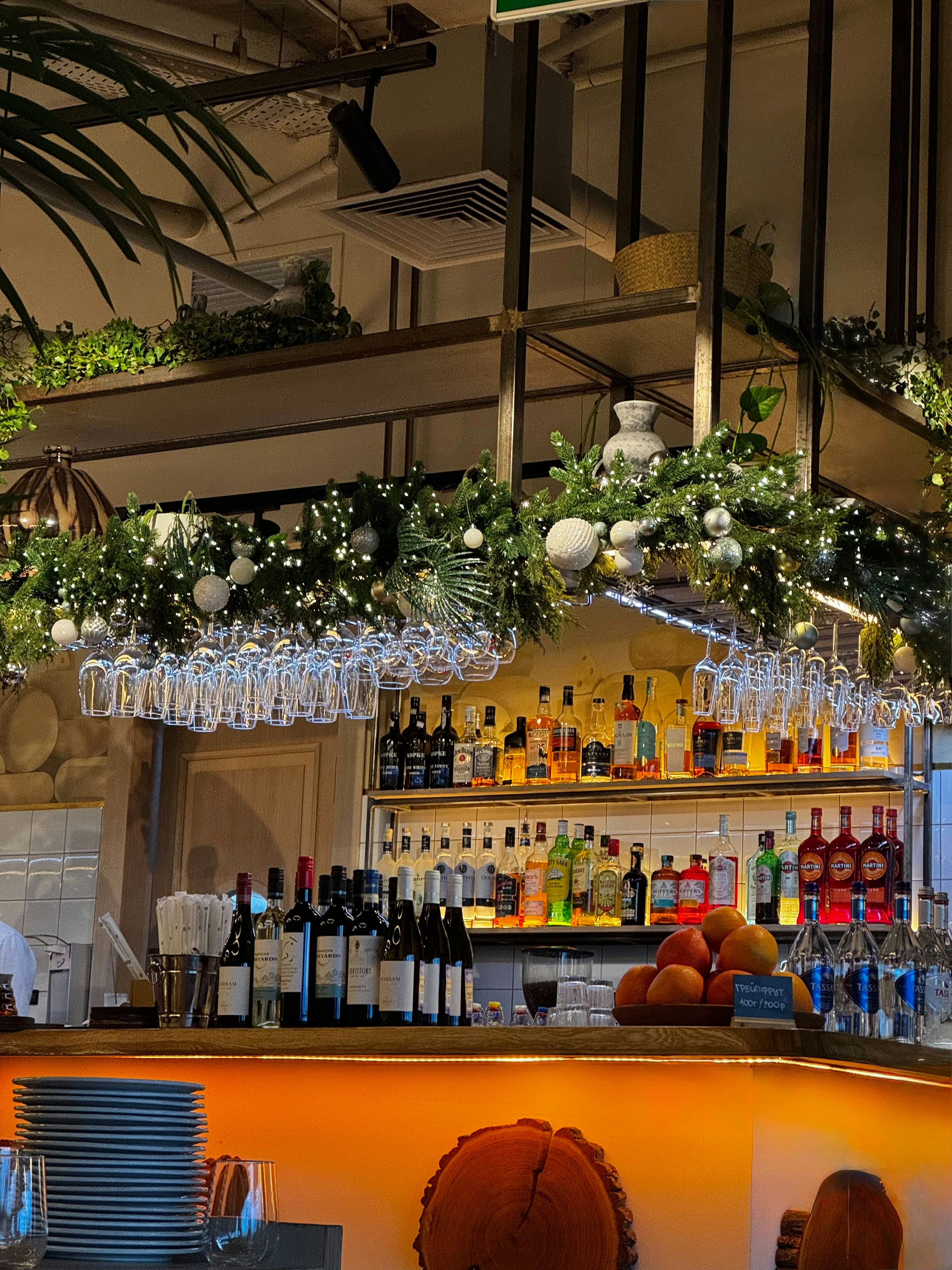 Festive Bar Canopy: Lights, Glasses, and Bottles Under Greenery