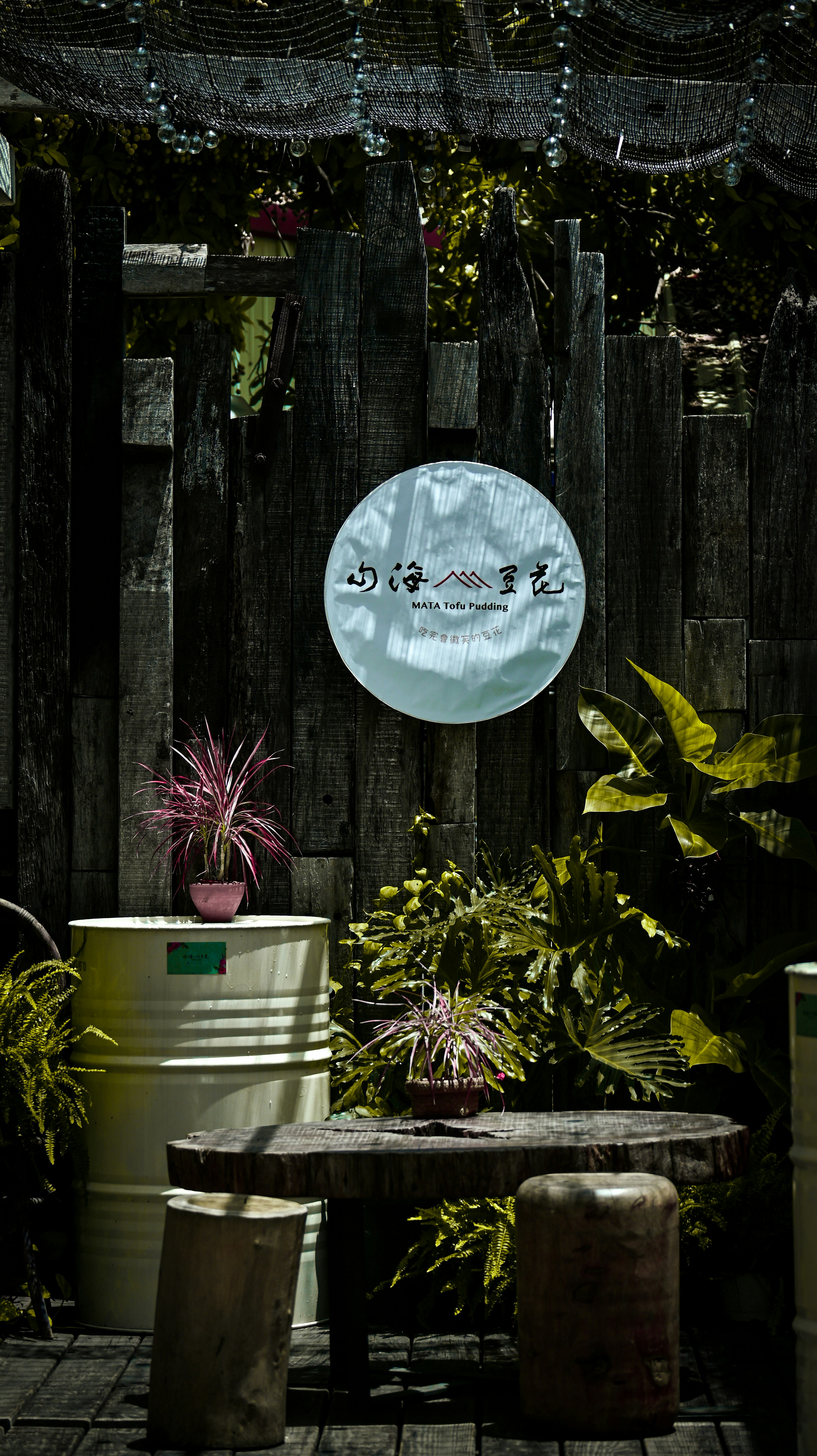 Circular Sign on a Weathered Fence Overlooking a Shade-dappled Garden Table