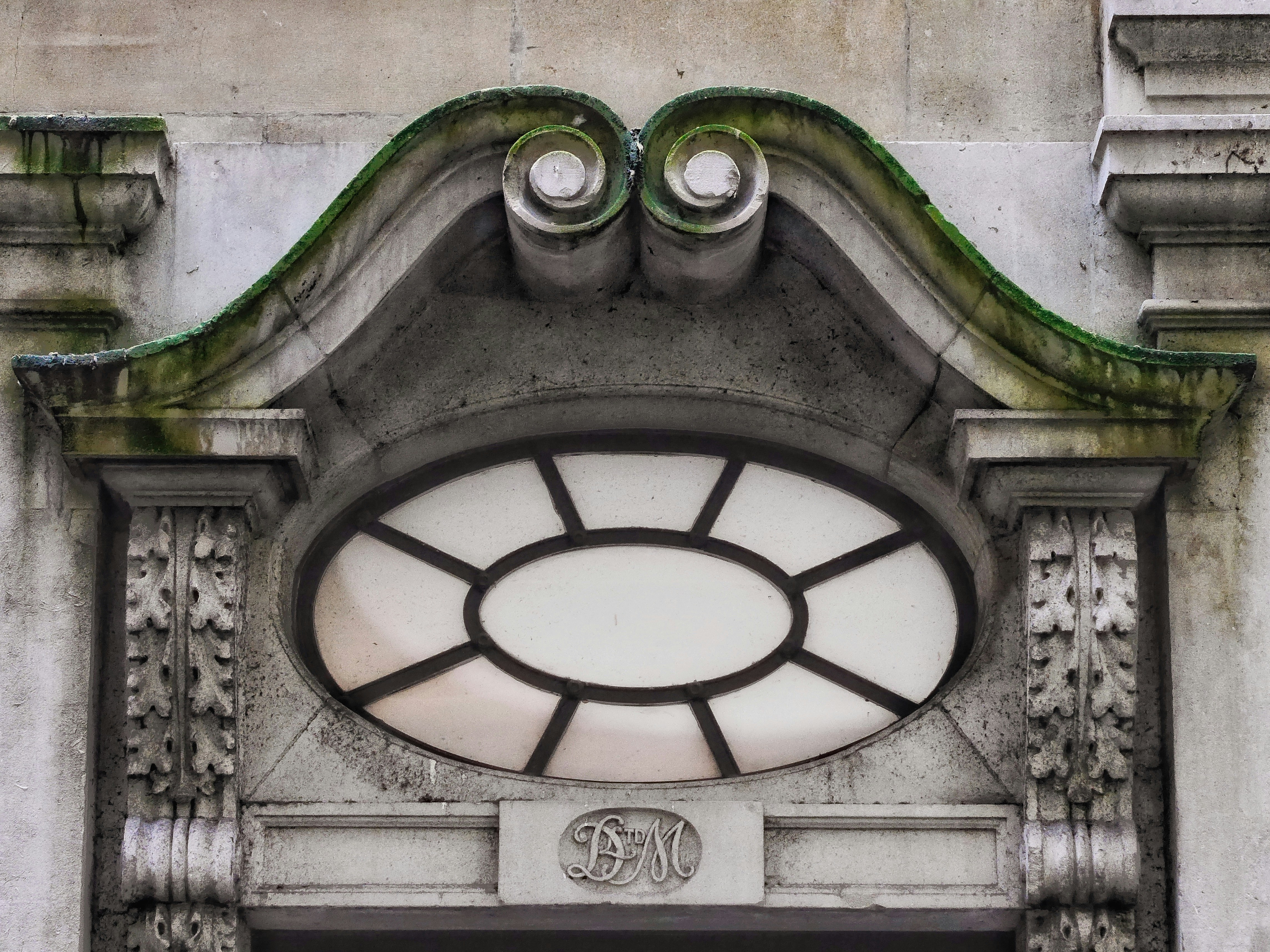 Moss-Trimmed Oval Window with Ornate Stone Carvings