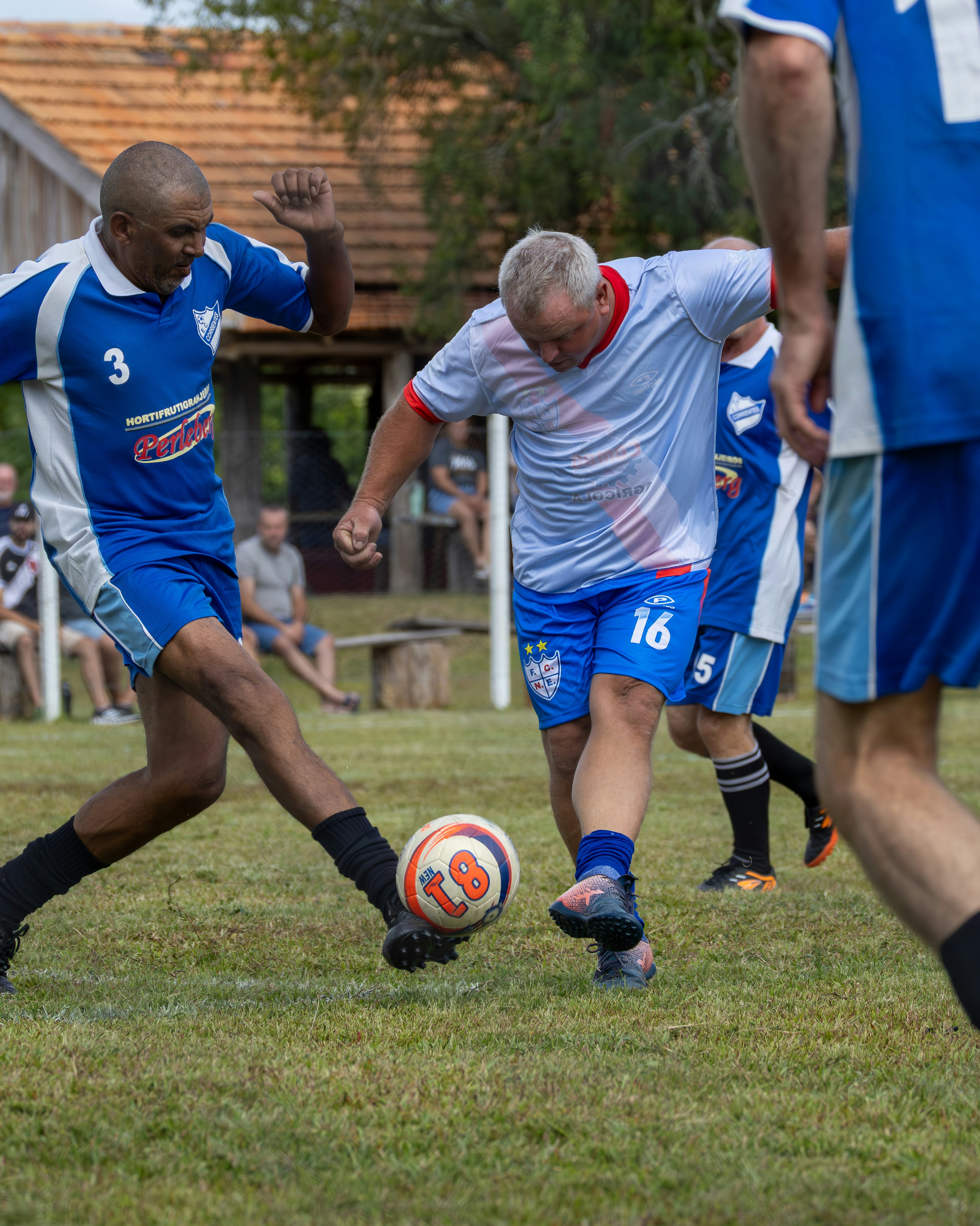 Midfield Challenge: A Determined Striker Drives the Ball Amid Blue Kits