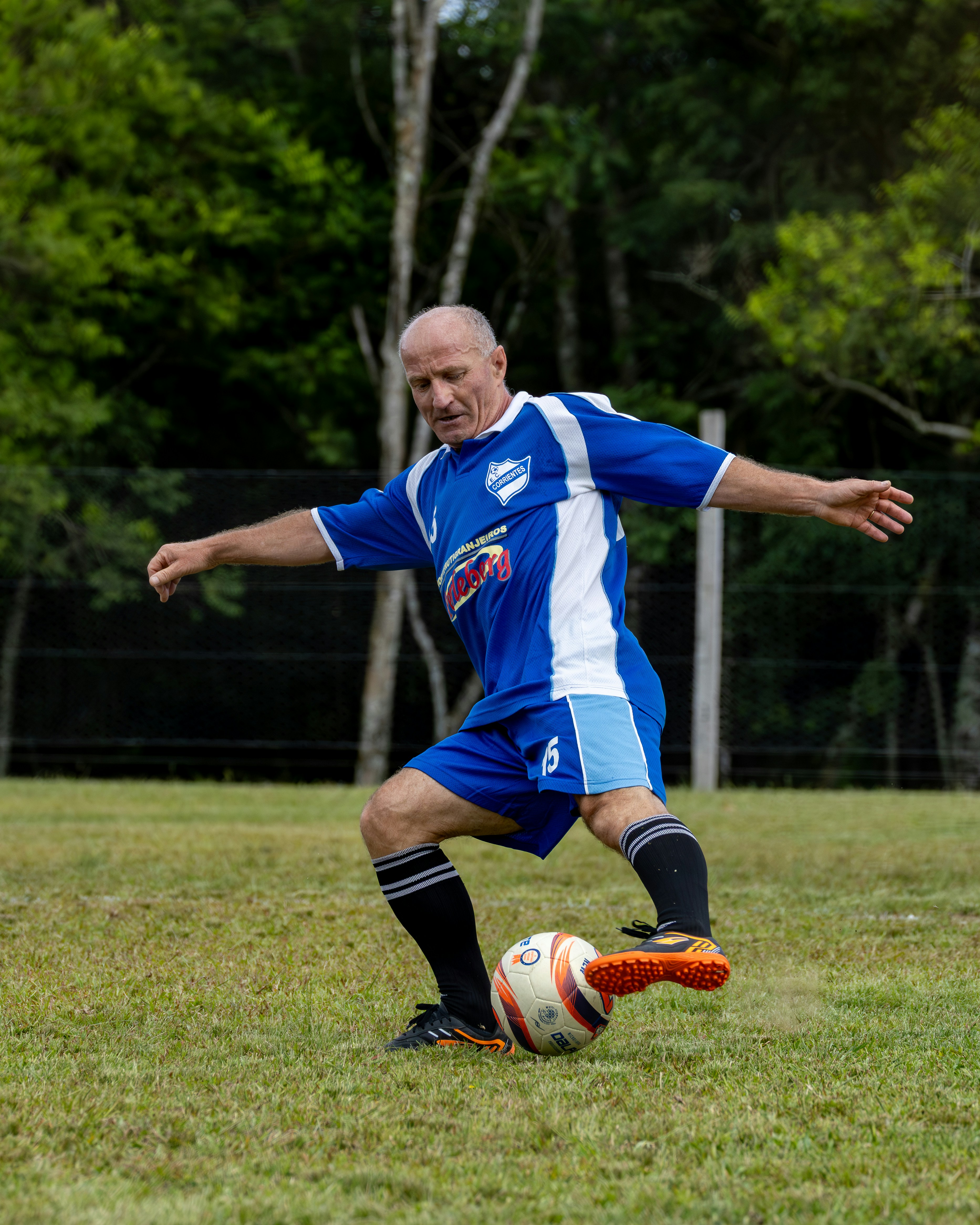 Midfield Maestro in Blue: A Dynamic Kick on Sunlit Grass