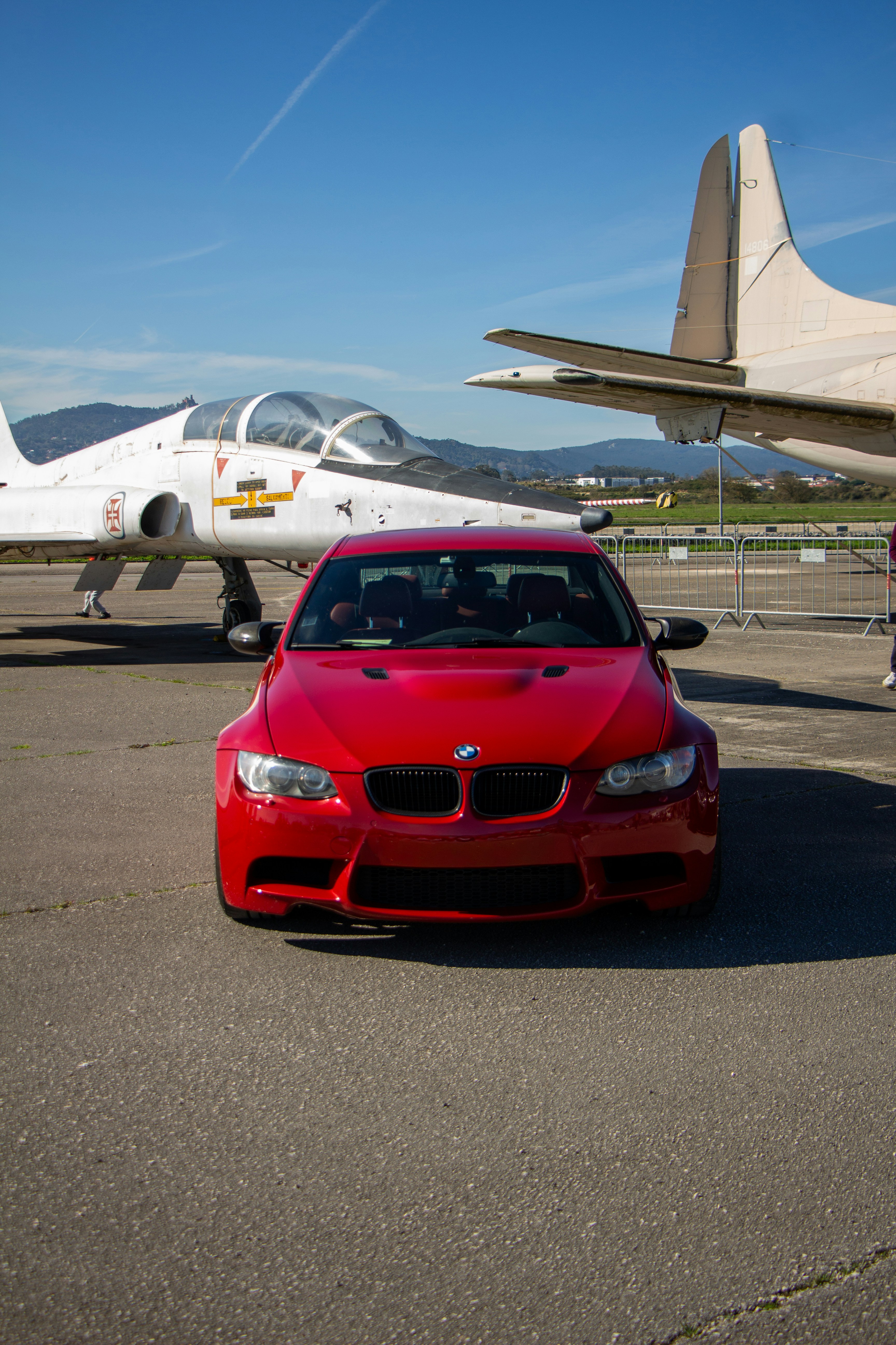 Red Fury on the Tarmac: Front View of BMW Beside Aircraft