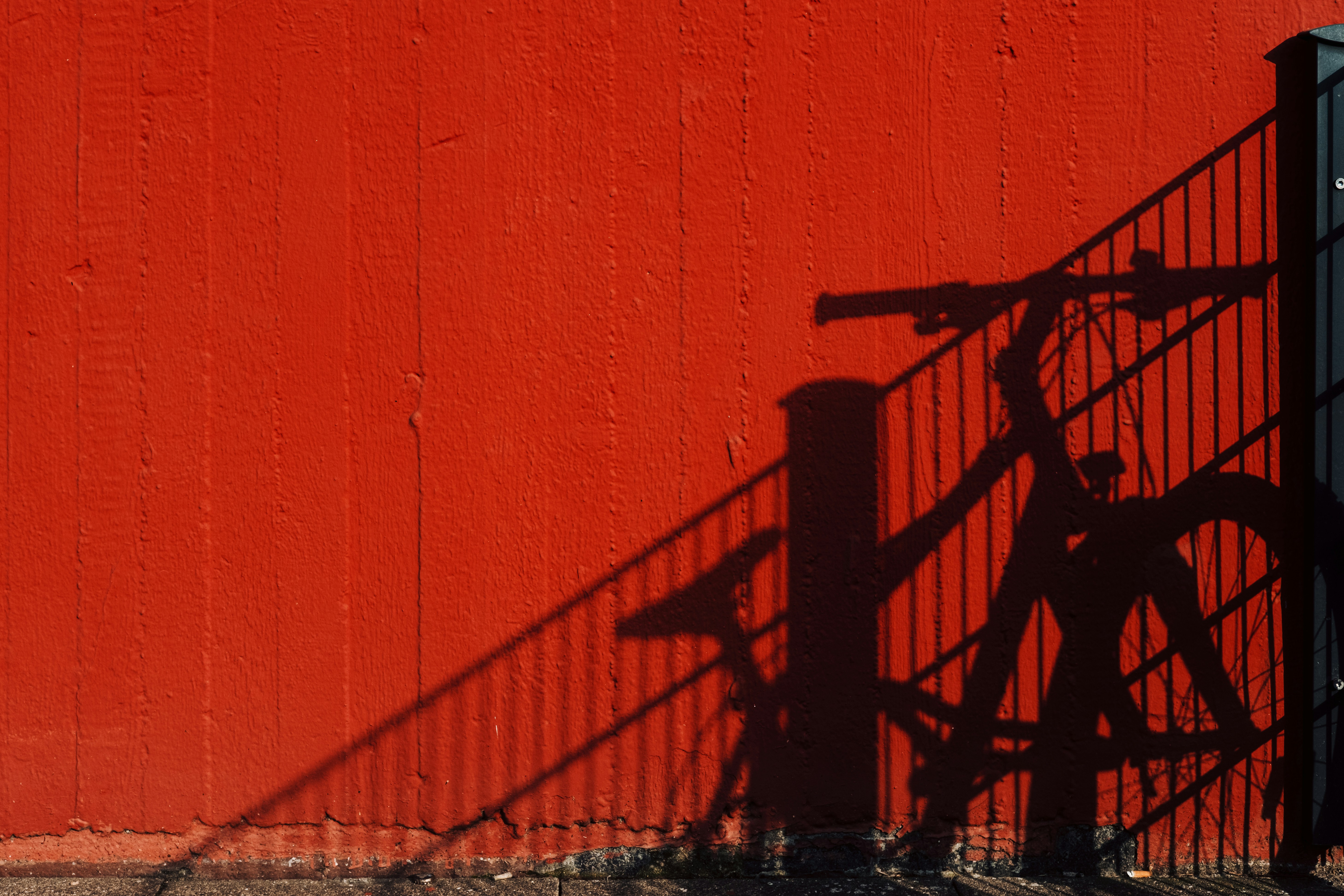 Shadowed Railing Cast on a Bold Red Wall