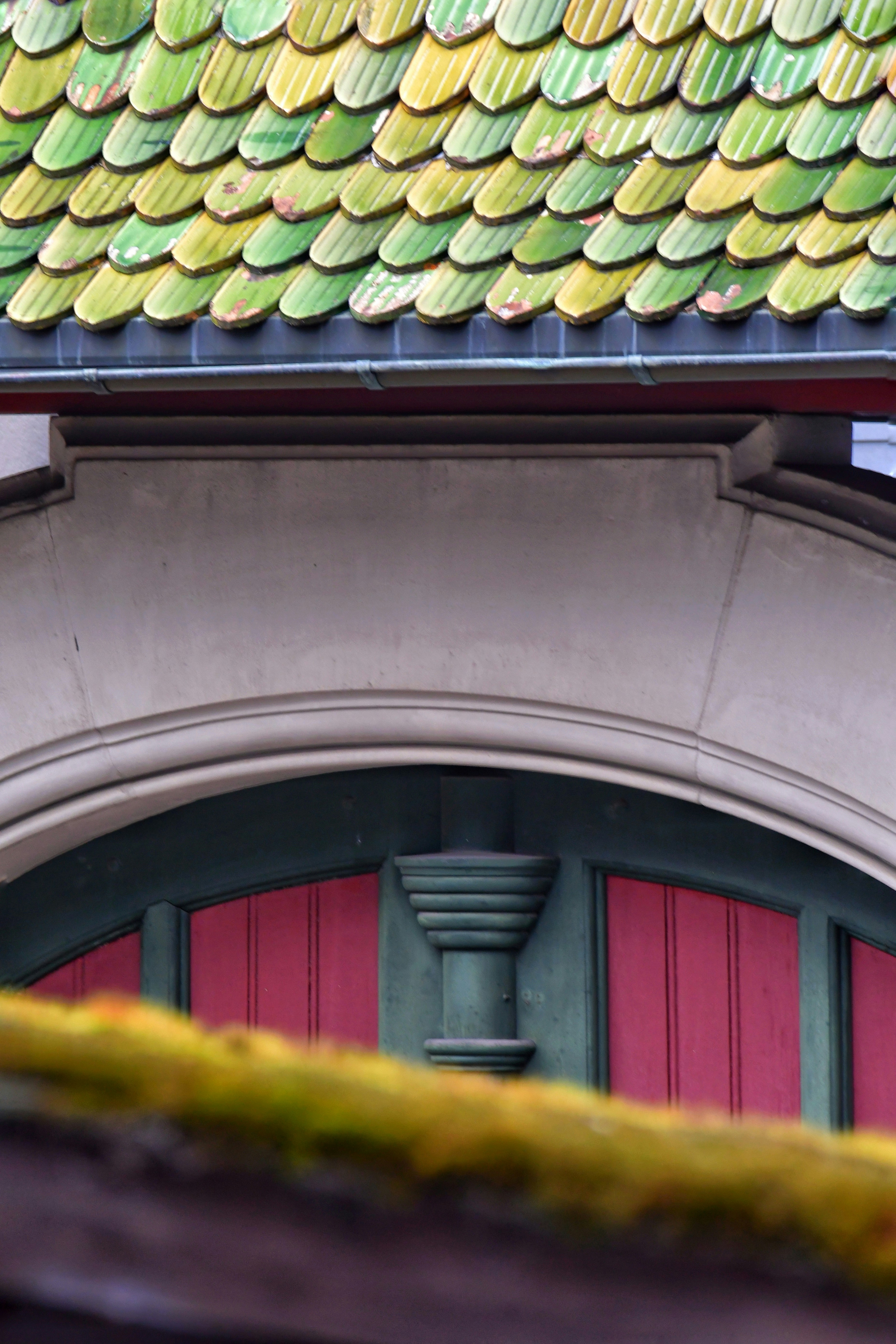 Archway Rhythm: Colorful Roof Tiles Framing an Old Facade