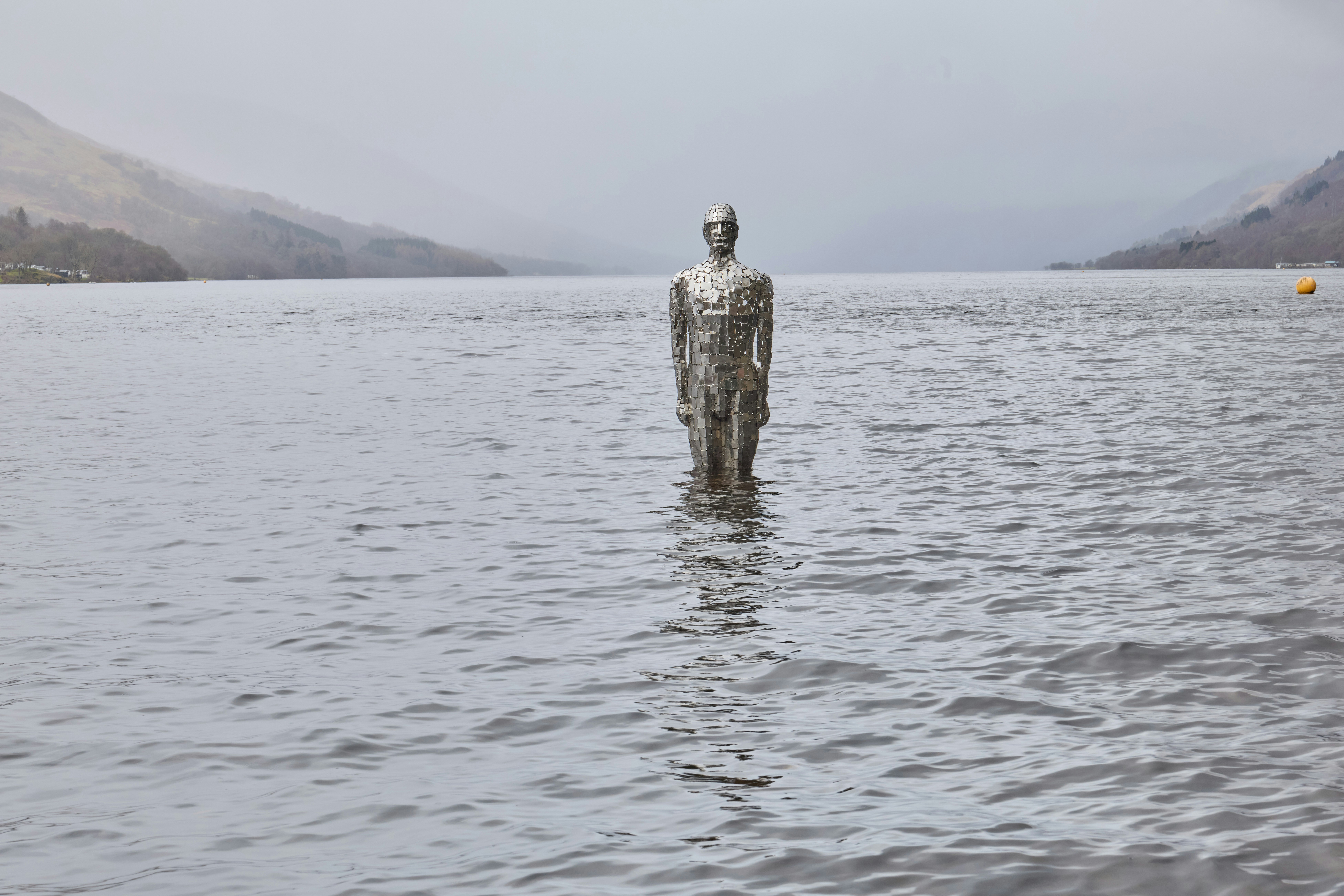 Statue Emerges from the Lake: A Silvery Figure in Distant Mist