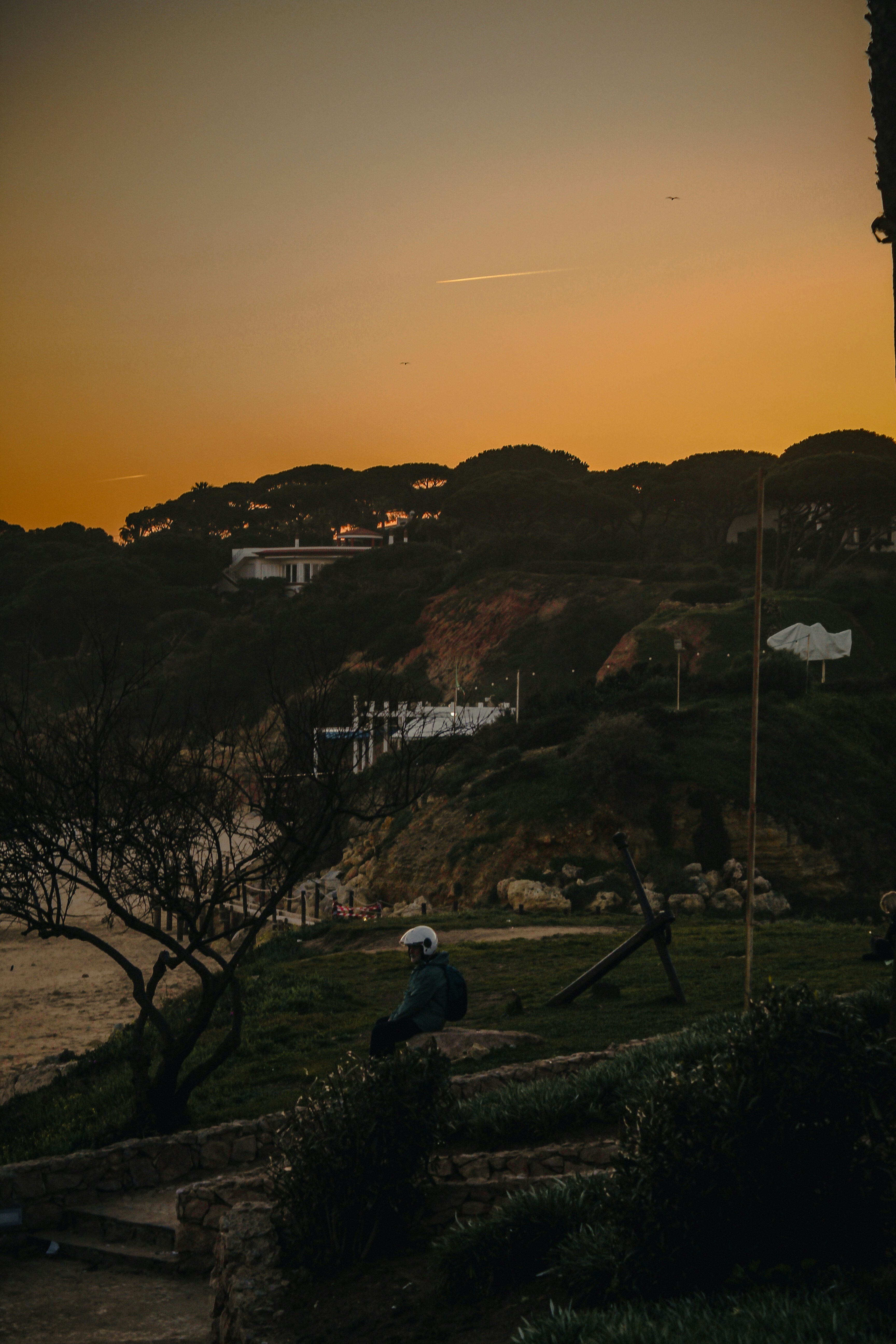 Beneath the Orange Dusk: A Lone Figure by the Cliffside