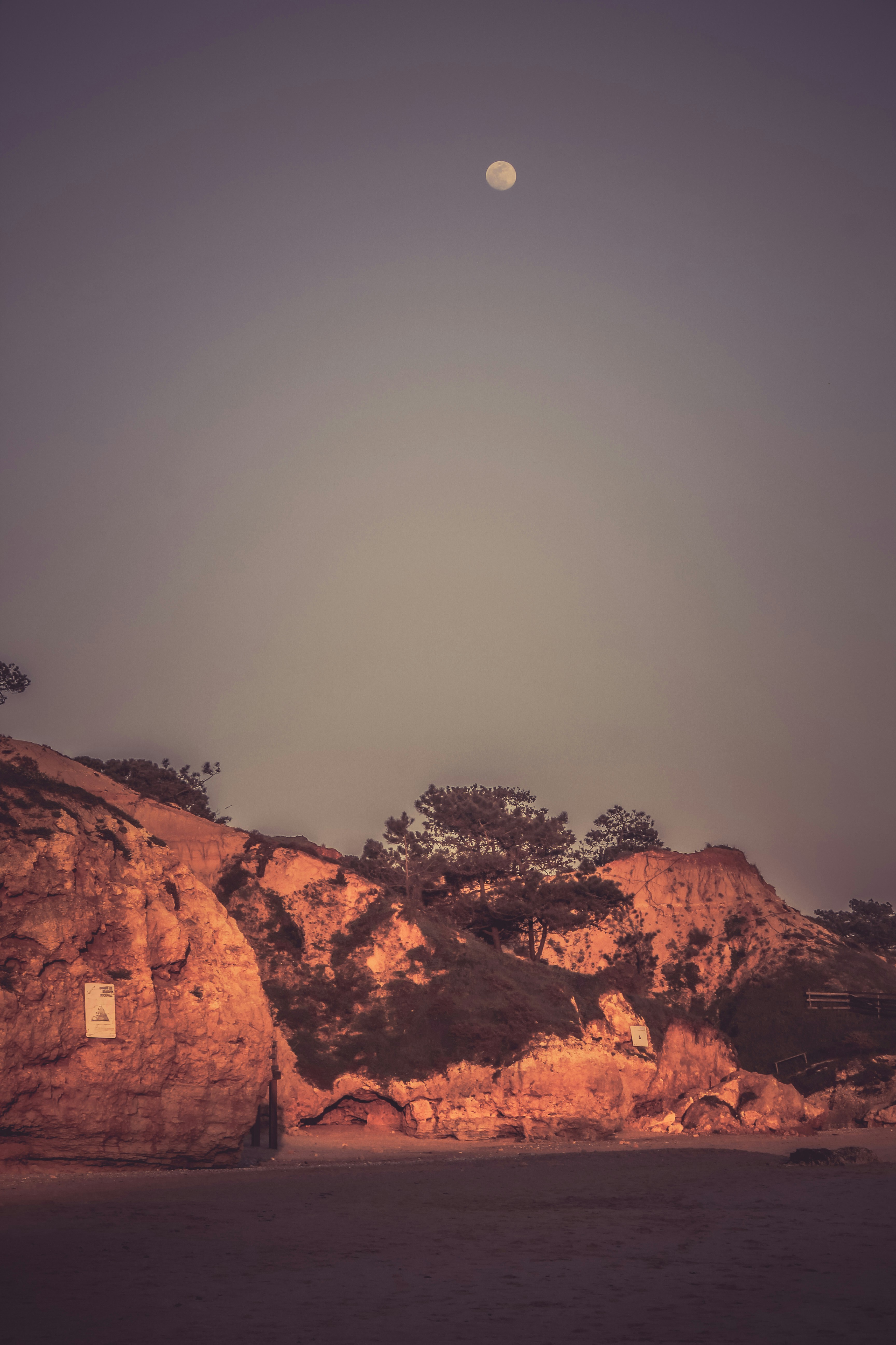 Full moon over rocky cliffs at dusk
