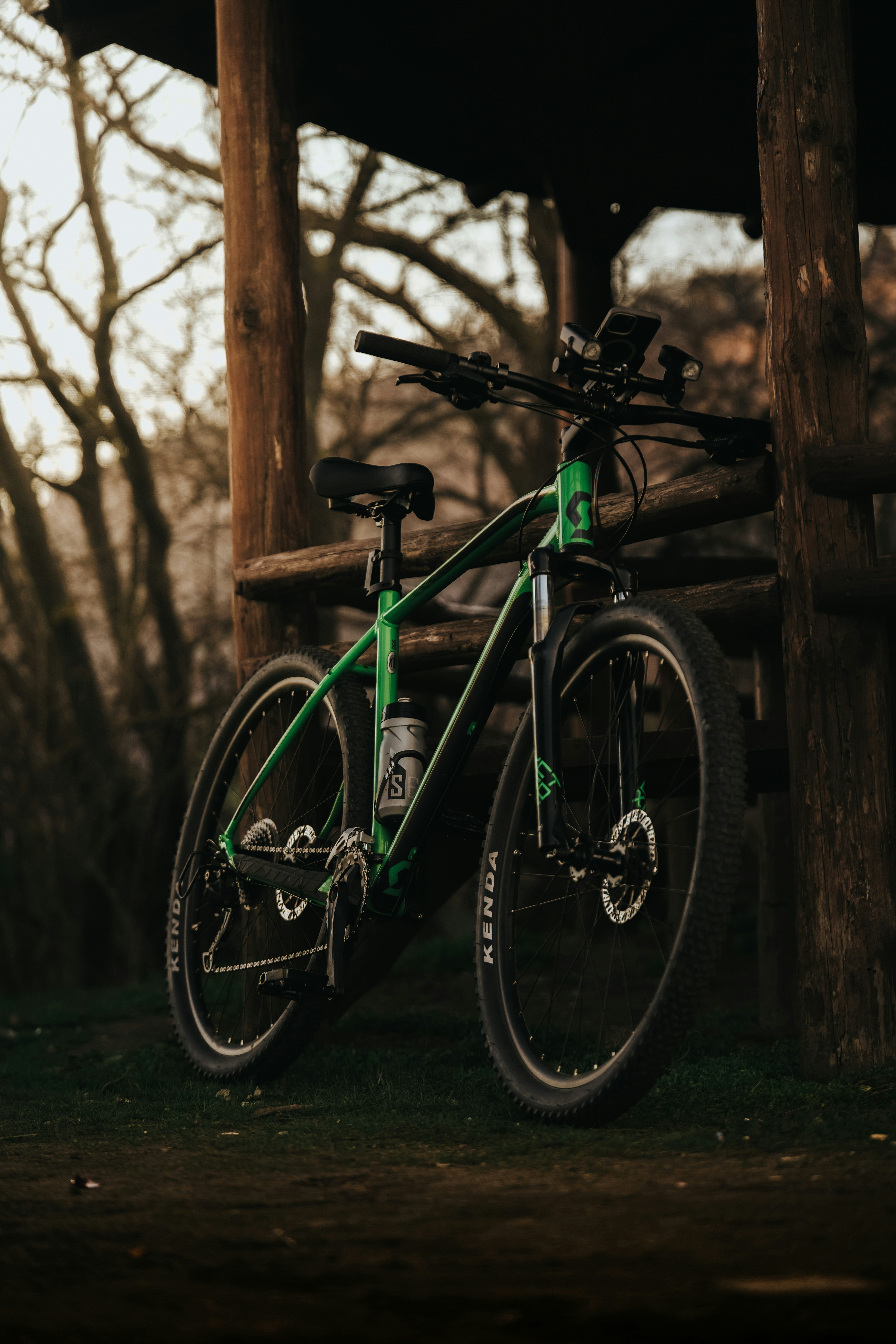 Green Mountain Bike Resting Against Rustic Balcony in Dappled Evening Light