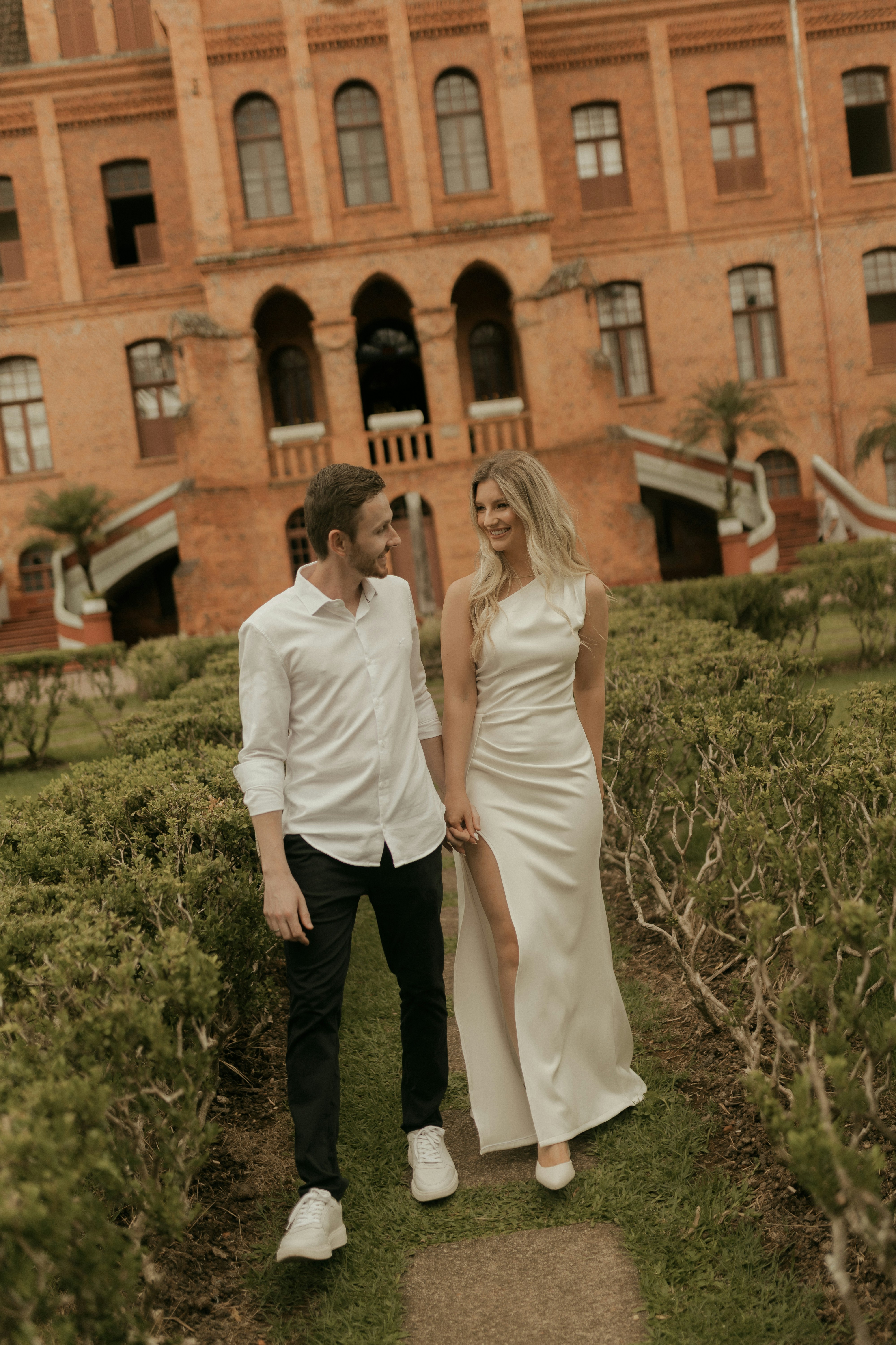 Couple in white at a brick estate garden
