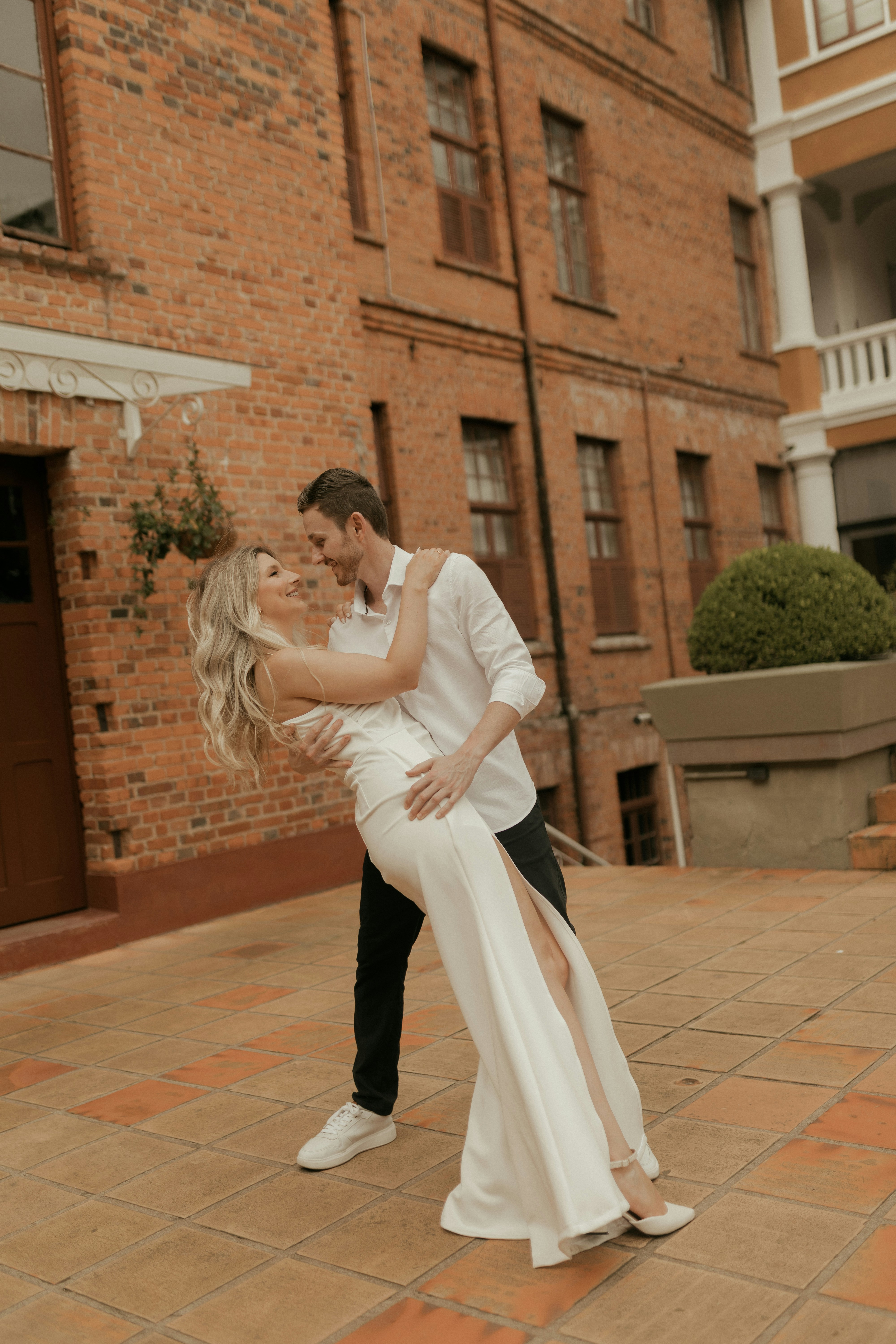 Dancing on Brick and Tile: A Bride in White and Groom in Pale Light