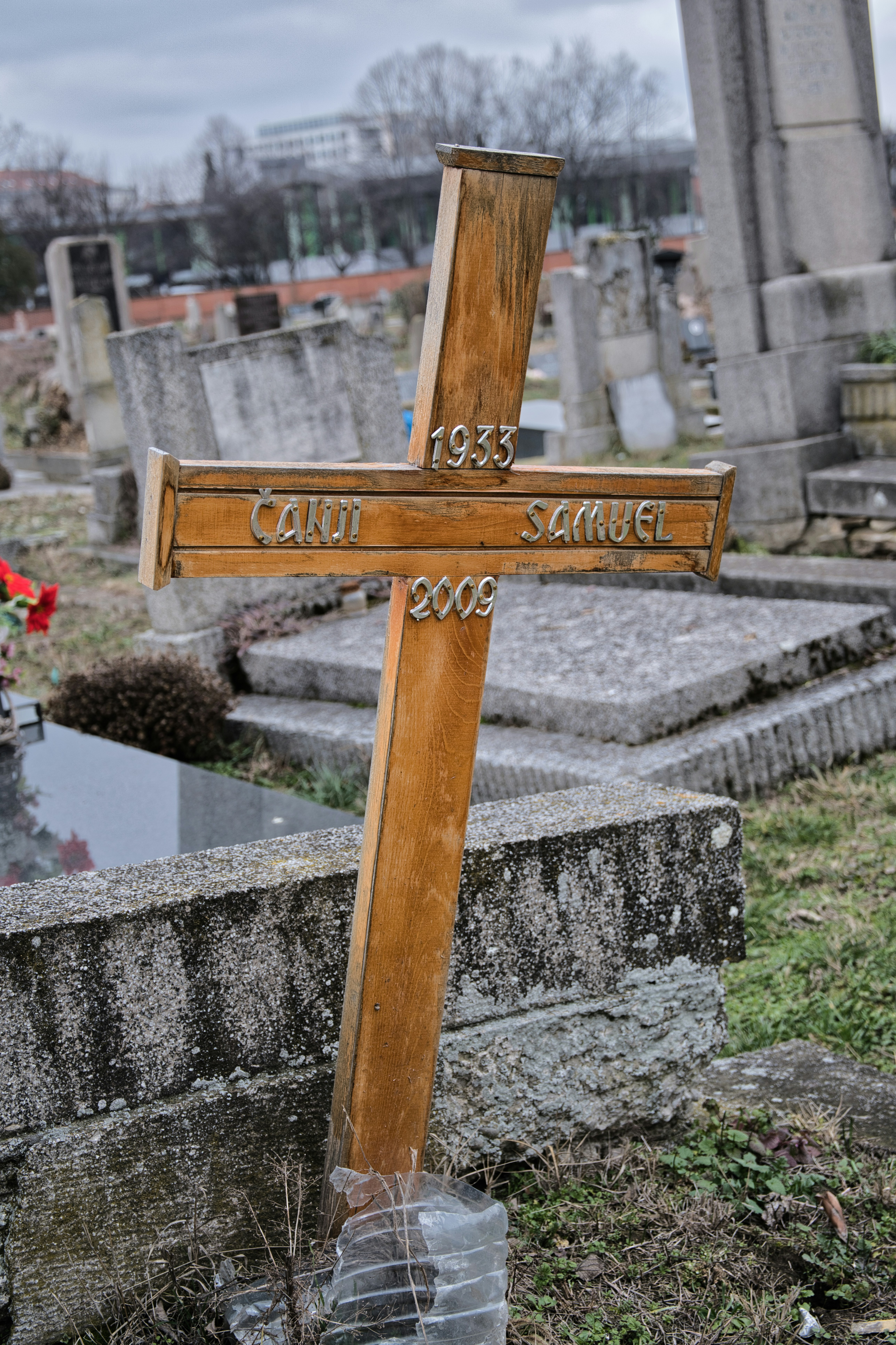 Wooden Cross Memorial Rising from Concrete Gravestones