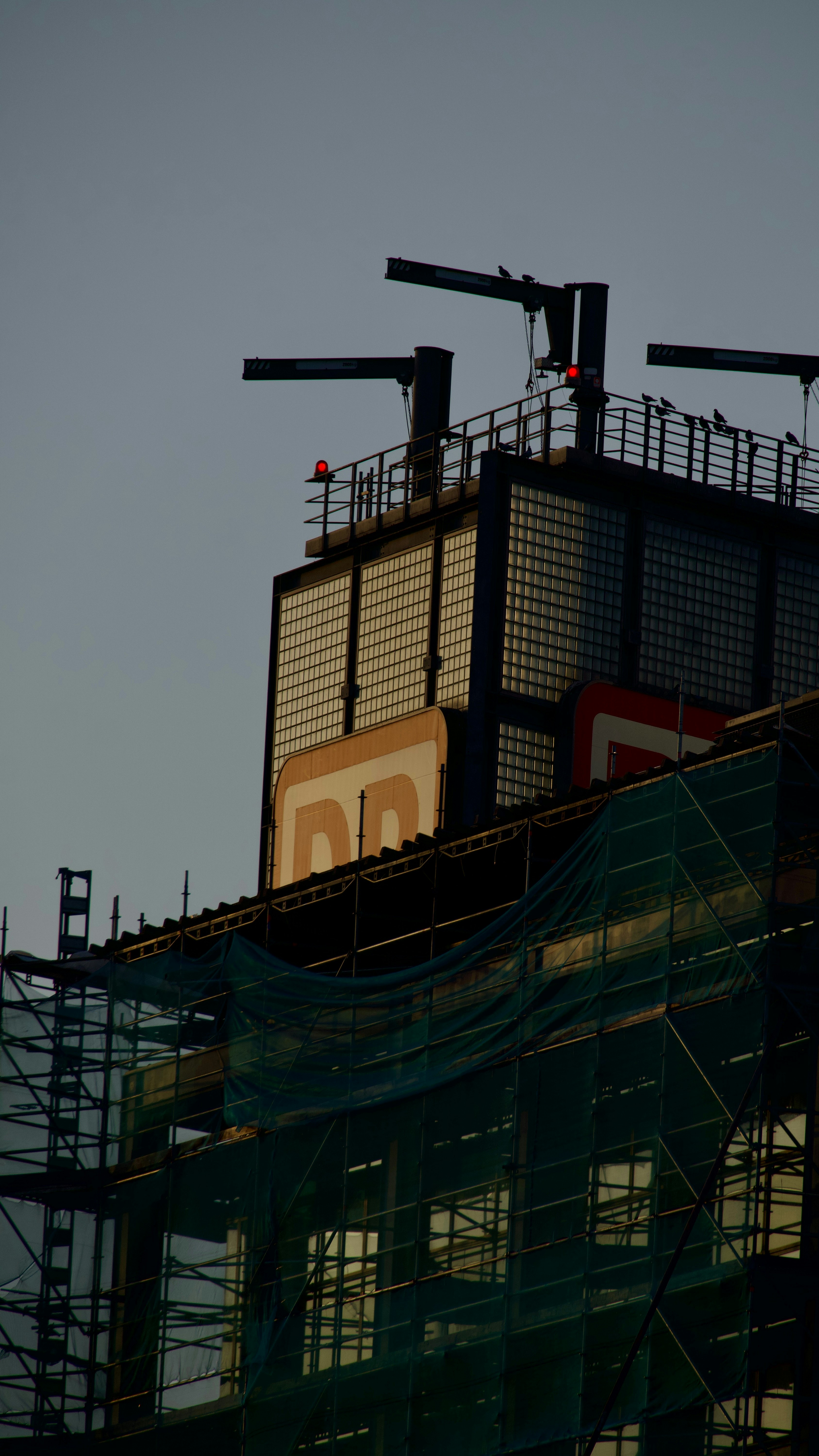 Towering Crane Silhouettes Above Under-Construction Glass Facade