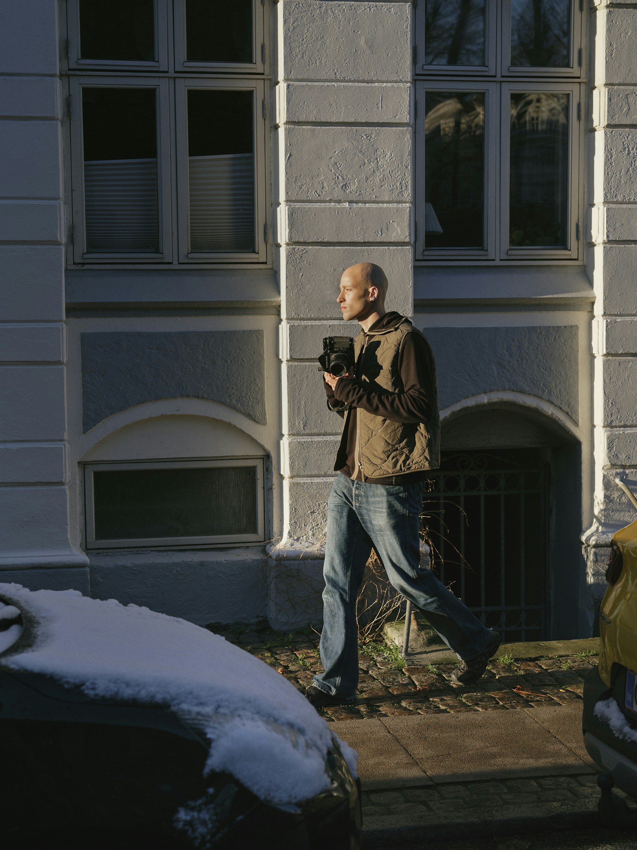 The Street Photographer strides along a sunlit facade