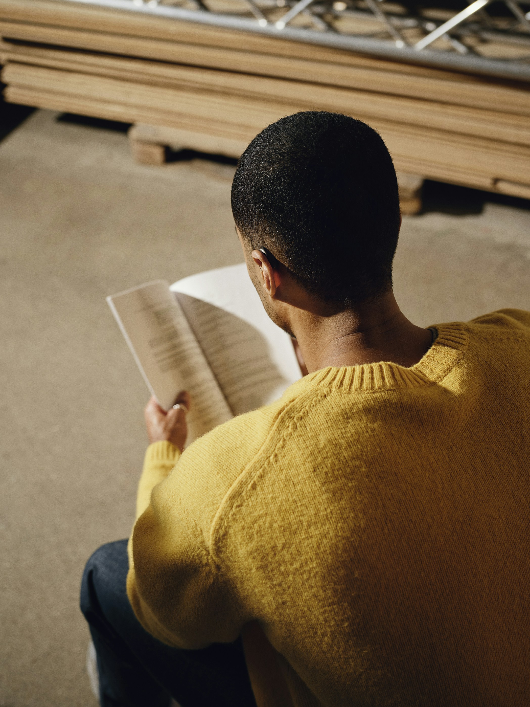 Reader with a Mustard Sweater: Quiet Focus in an Industrial Space