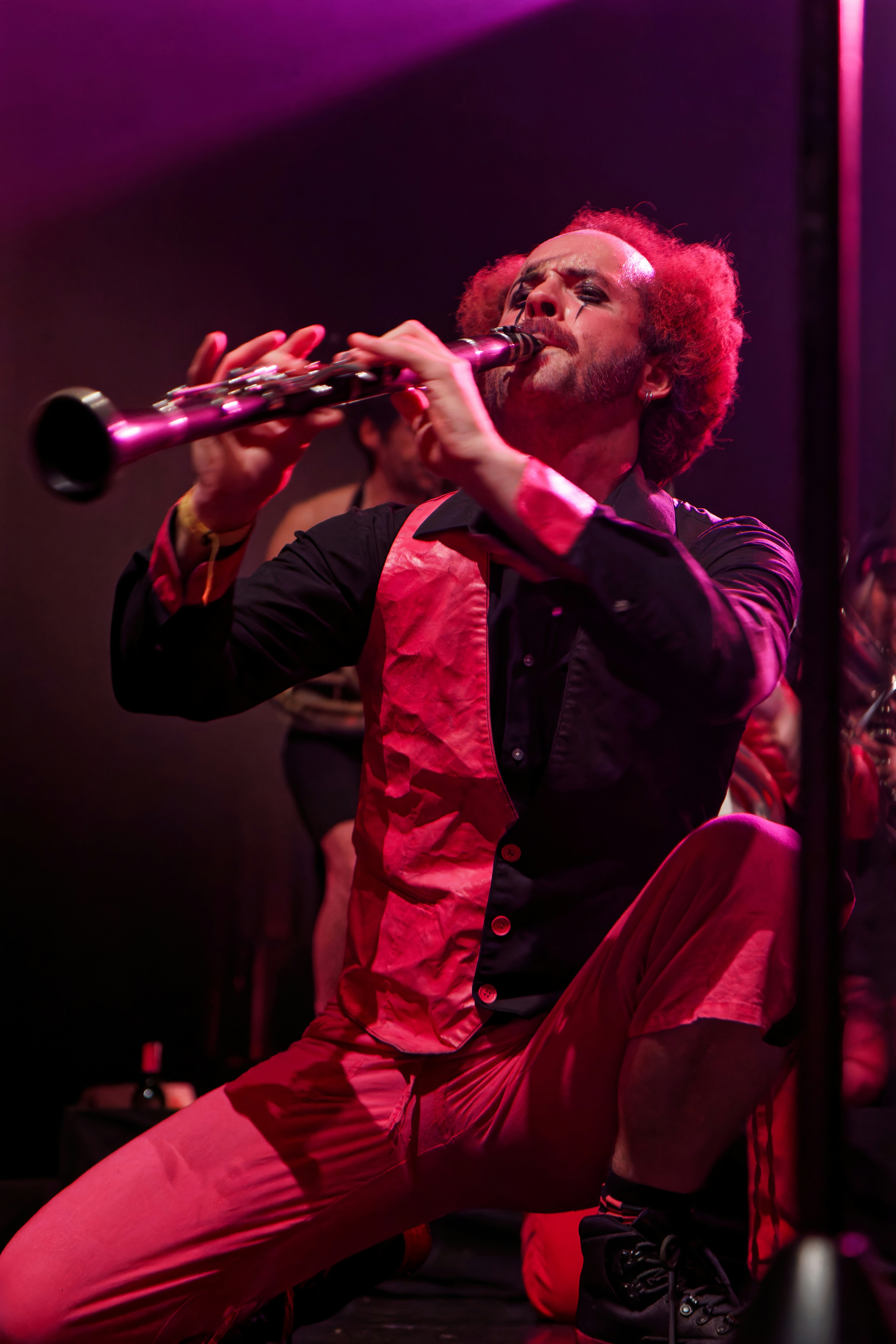 A performer in clown makeup plays a clarinet on stage. photo – Free ...