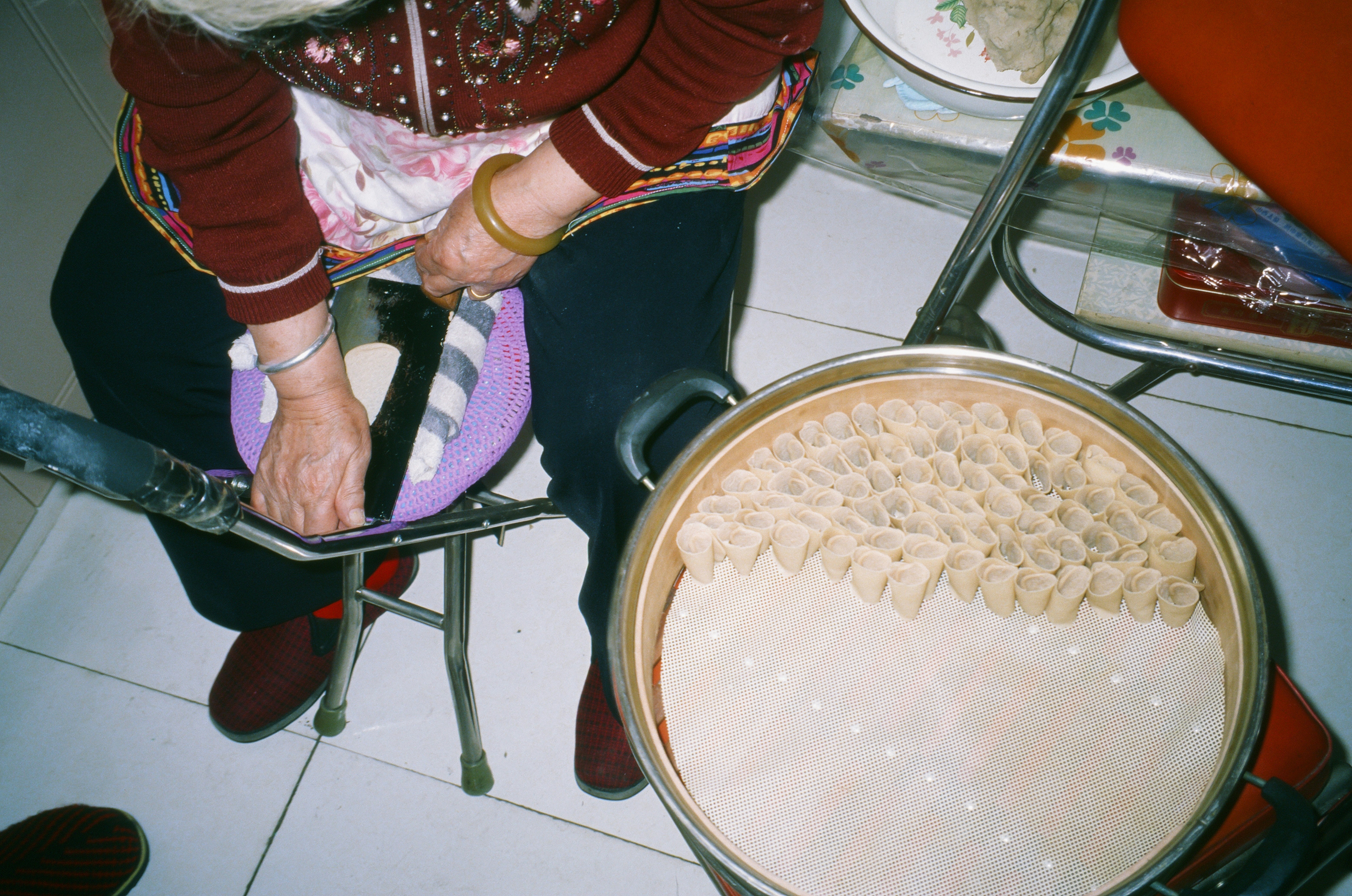 Hands preparing dumplings in a bamboo steamer basket.