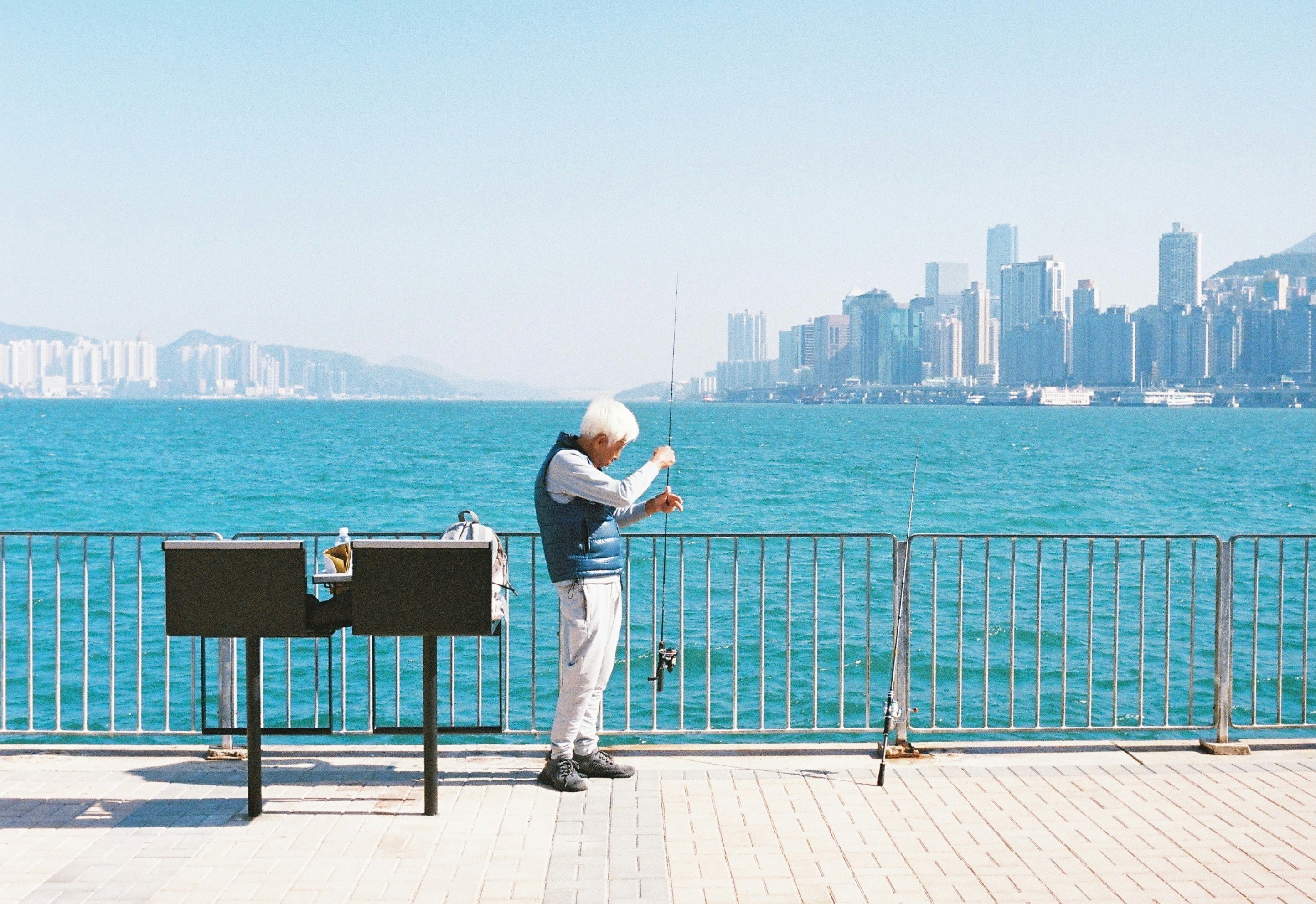 Captain at the Rail: A Senior Angler Casts Toward the City