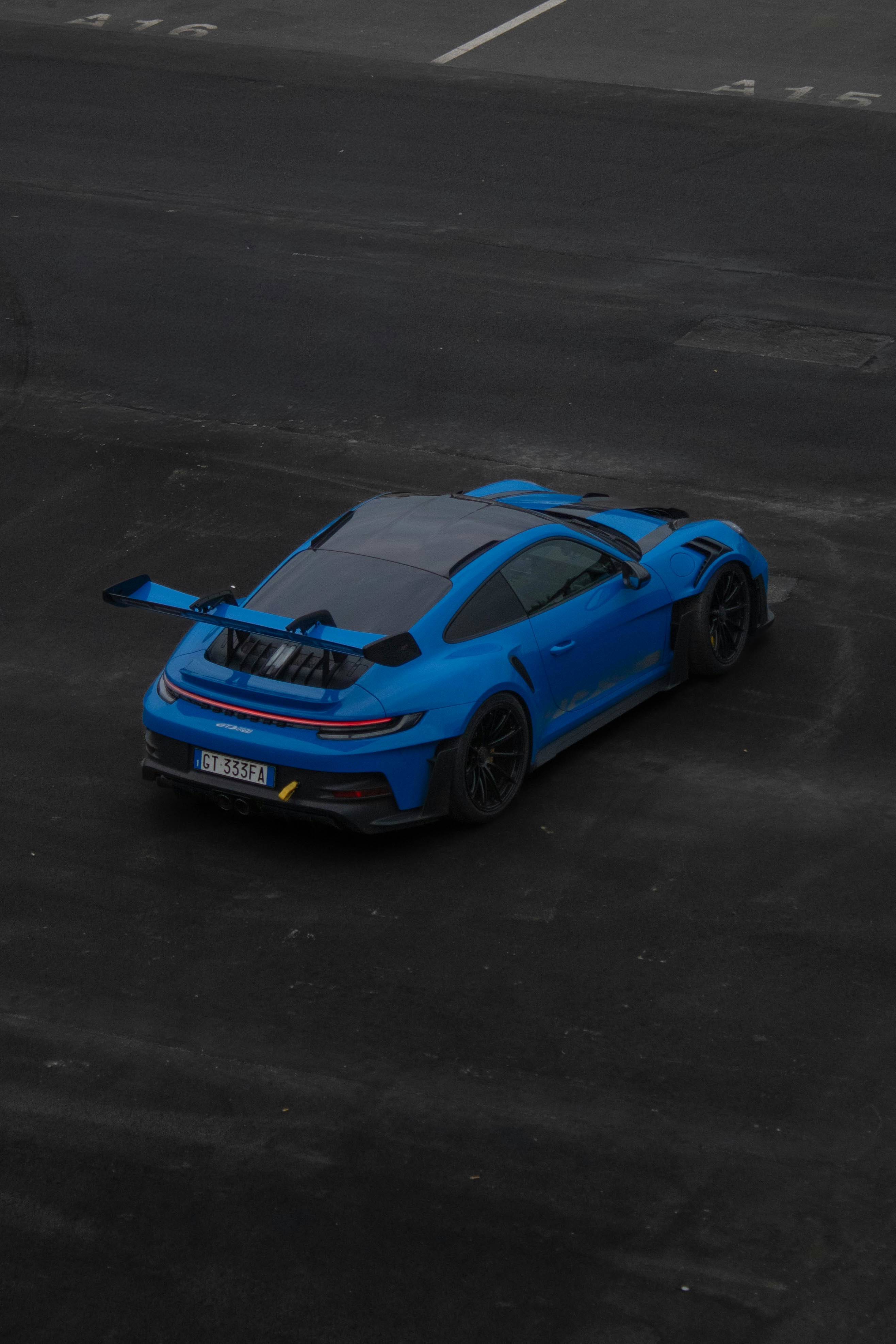 Blue racer on dark tarmac: a high-angle podium shot
