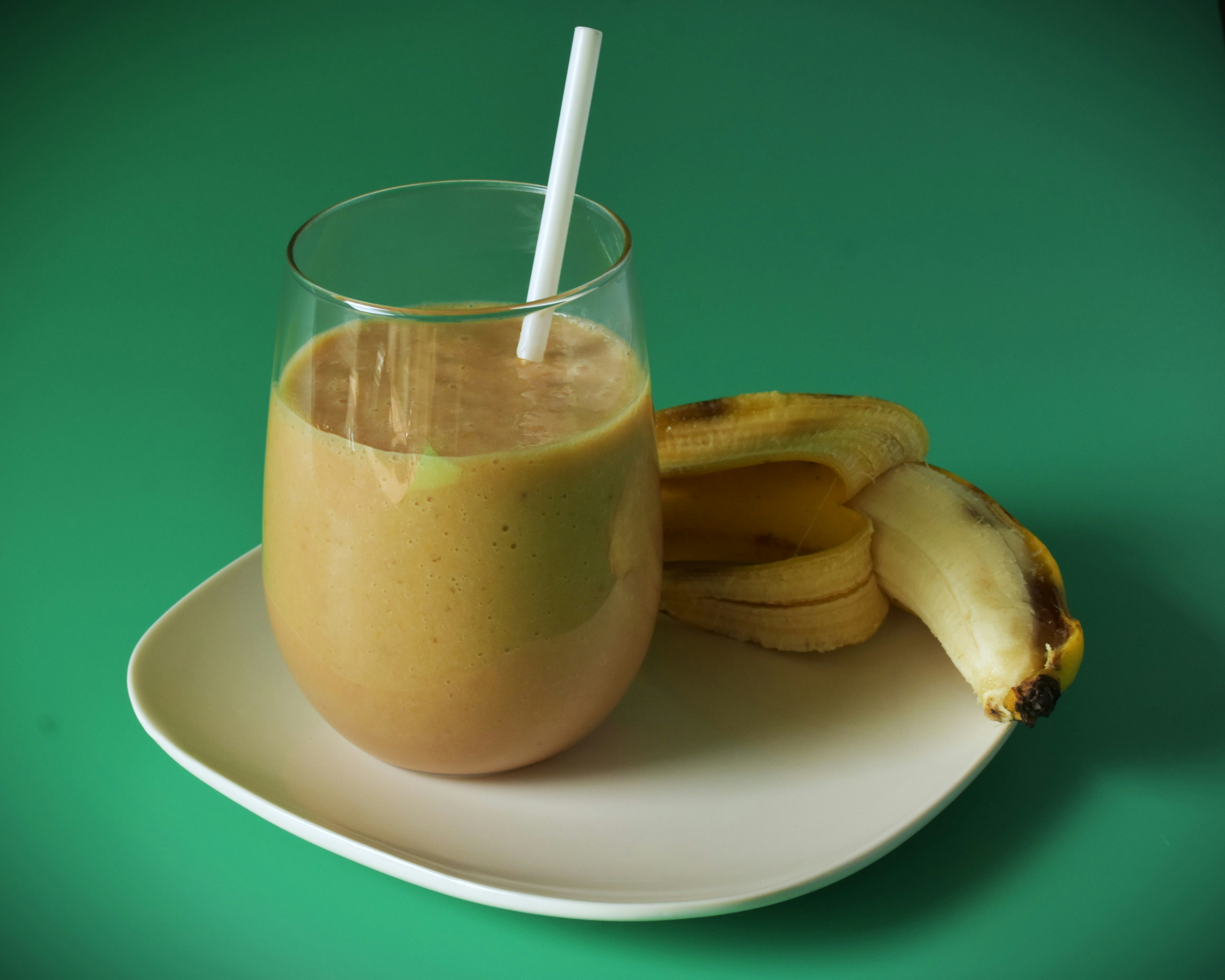 Banana Smoothie on a White Plate: A Green Backdrop Highlighting a Creamy Drink