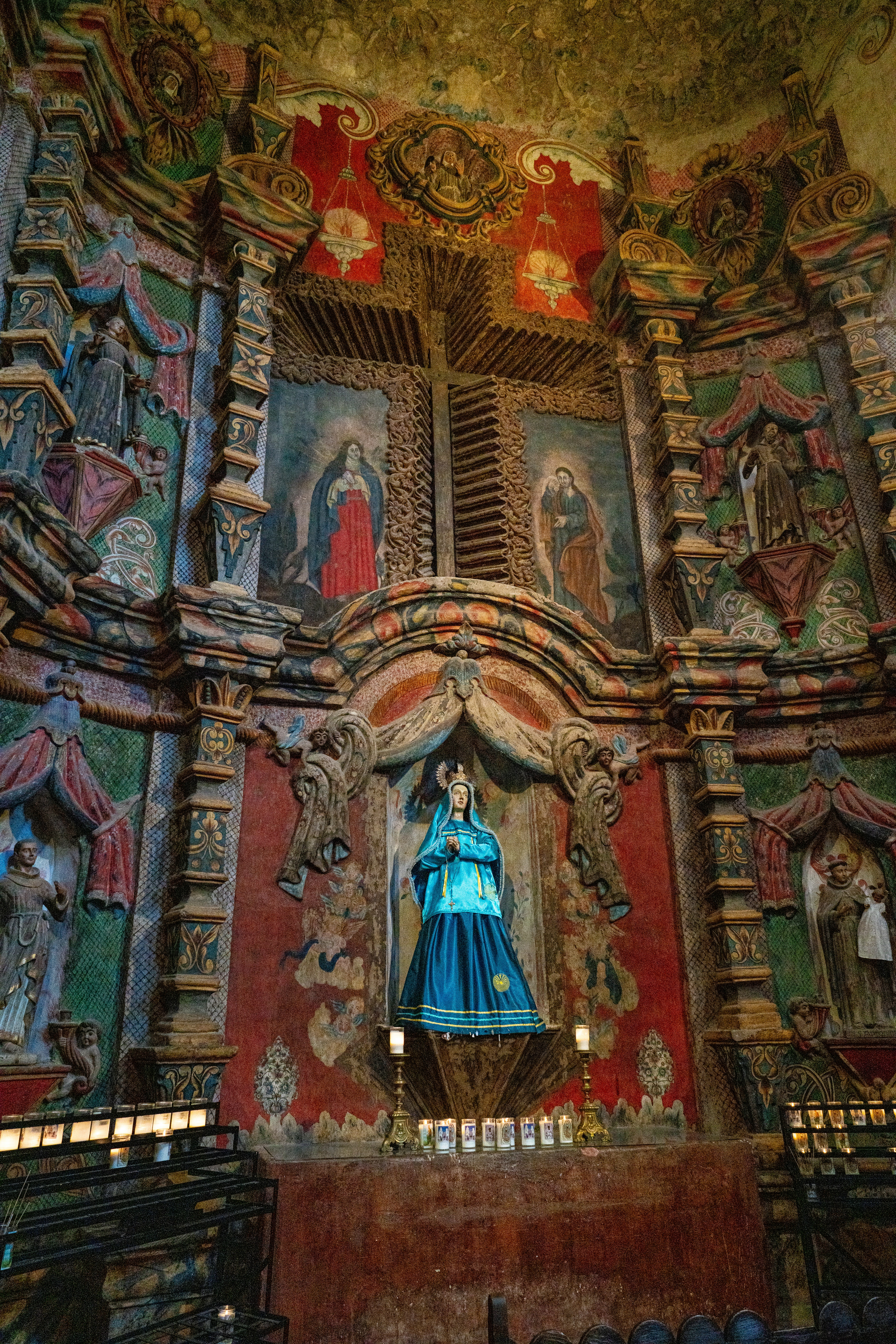Blue-robed statue centers a richly frescoed altarpiece in a cathedral chapel