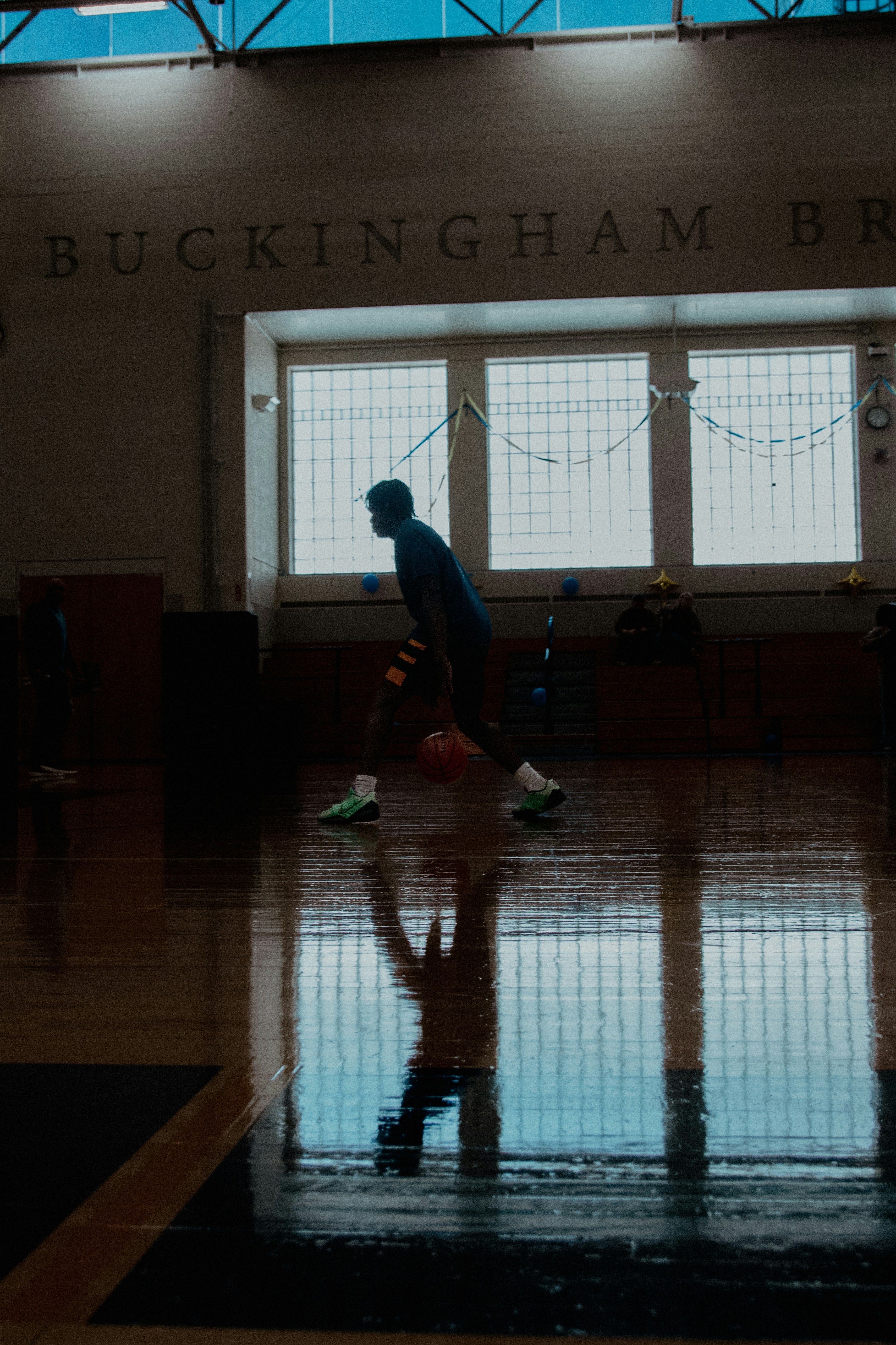 Silent Dribble: A lone player threads through the gym's reflective floor