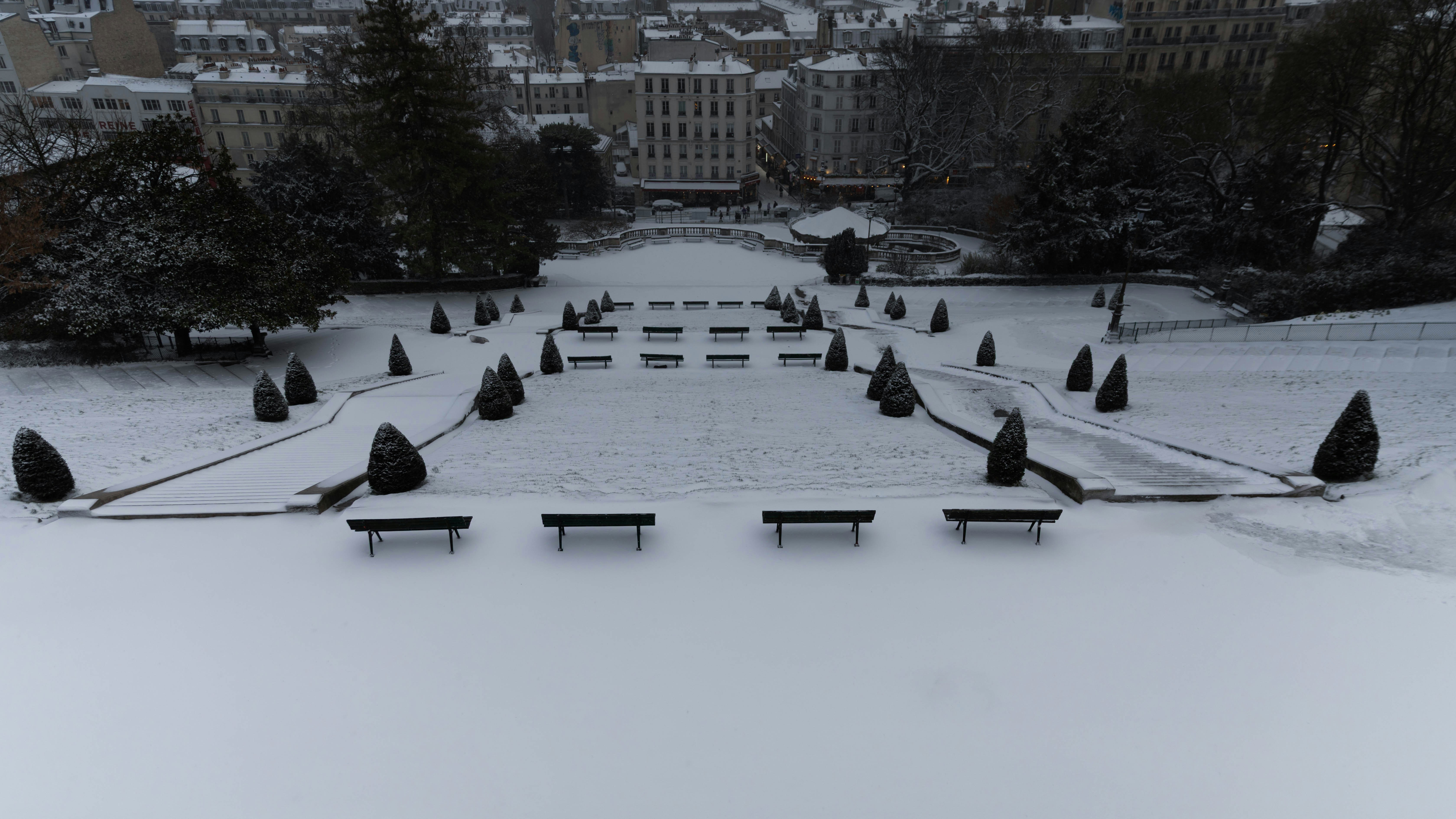 Symmetrical Winter Terrace: Snow-Covered Benches and Faded Pathway