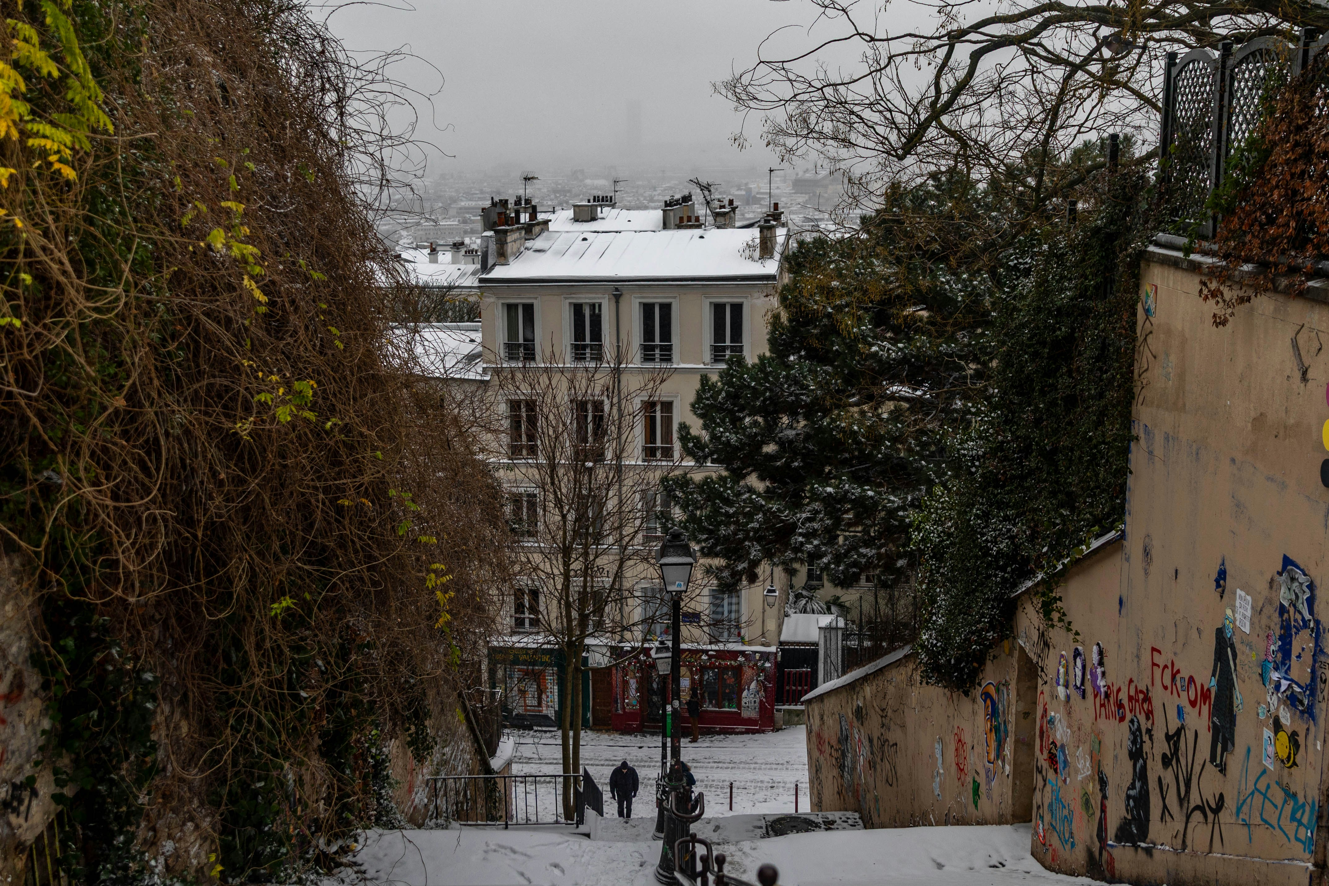 Snowy descent through a mural-clad stairwell toward a quiet city square