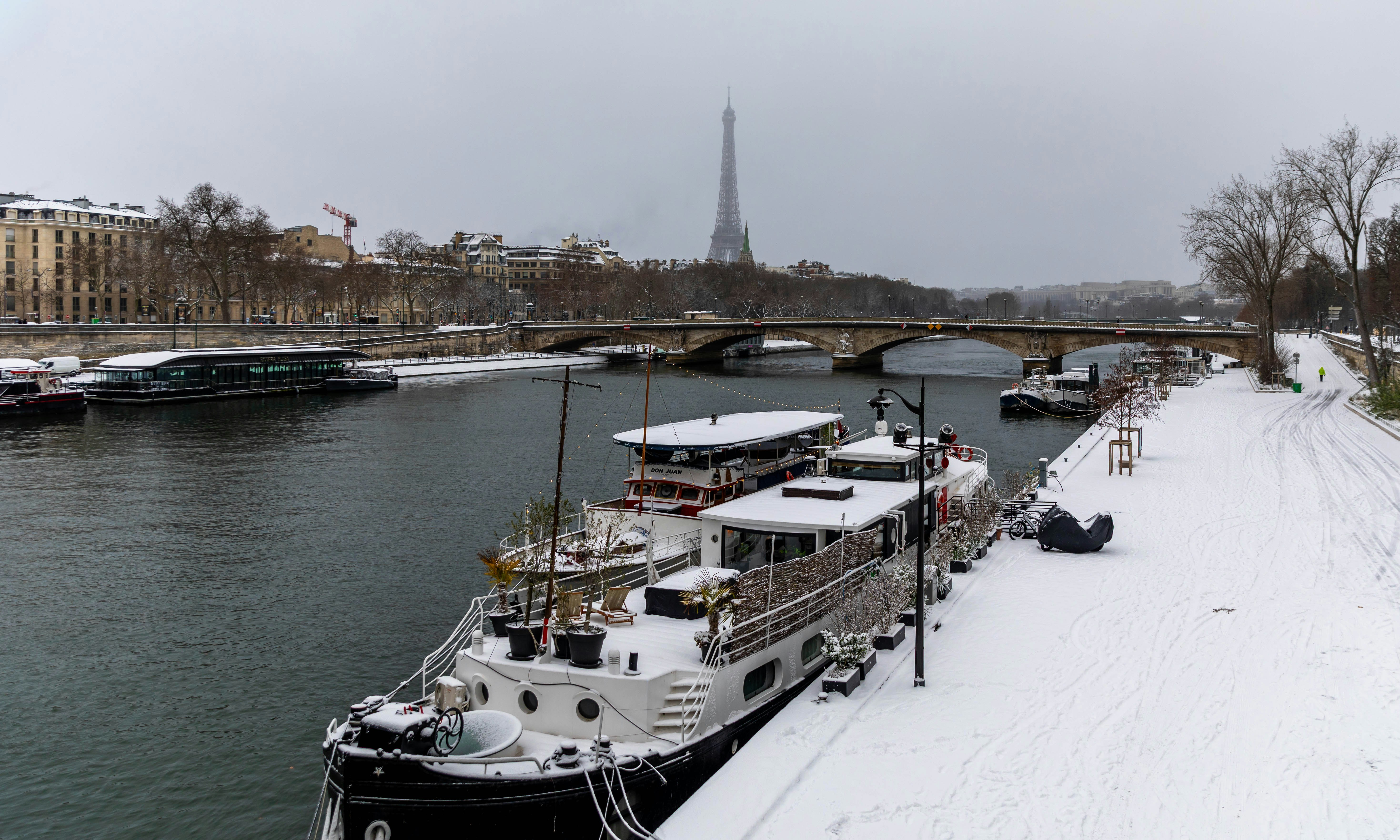 Snowy Seine Quiet: Boats Rest Along a French Riverbank with the Eiffel View in the Distance