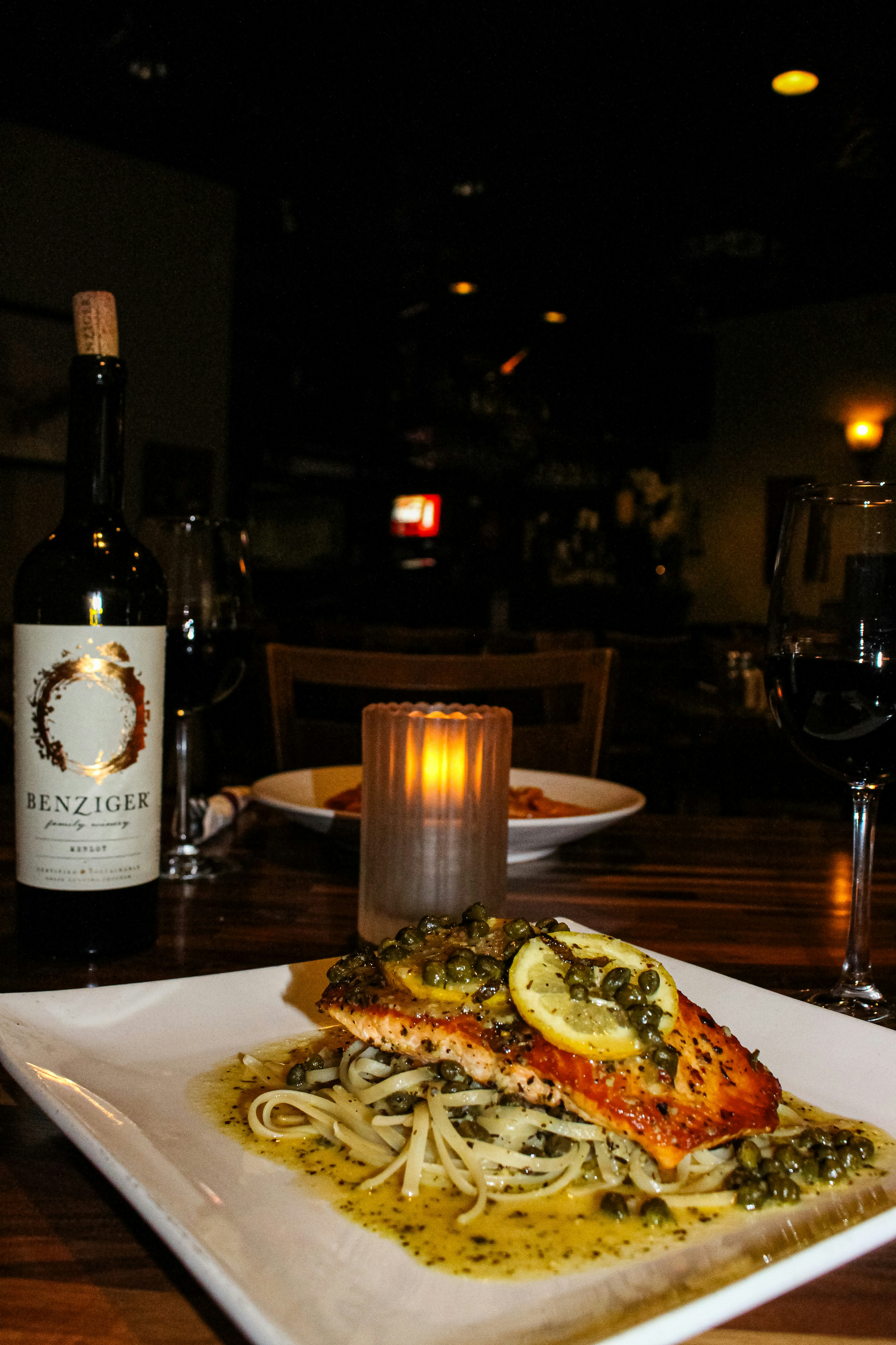 Salmon on herbed bed: a candlelit pasta dish at a cozy restaurant
