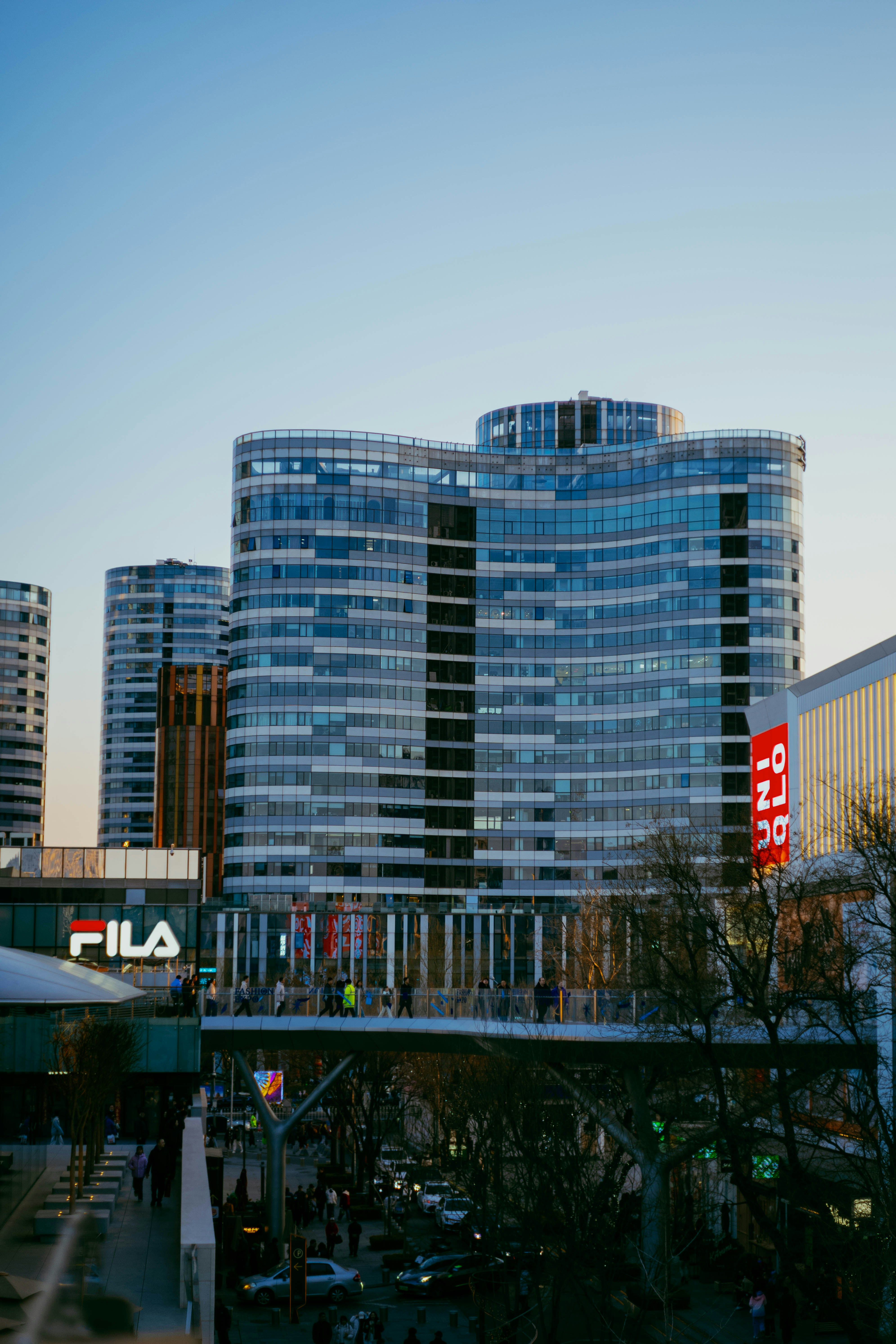 Glass-curved towers rising above a bustling shopping promenade