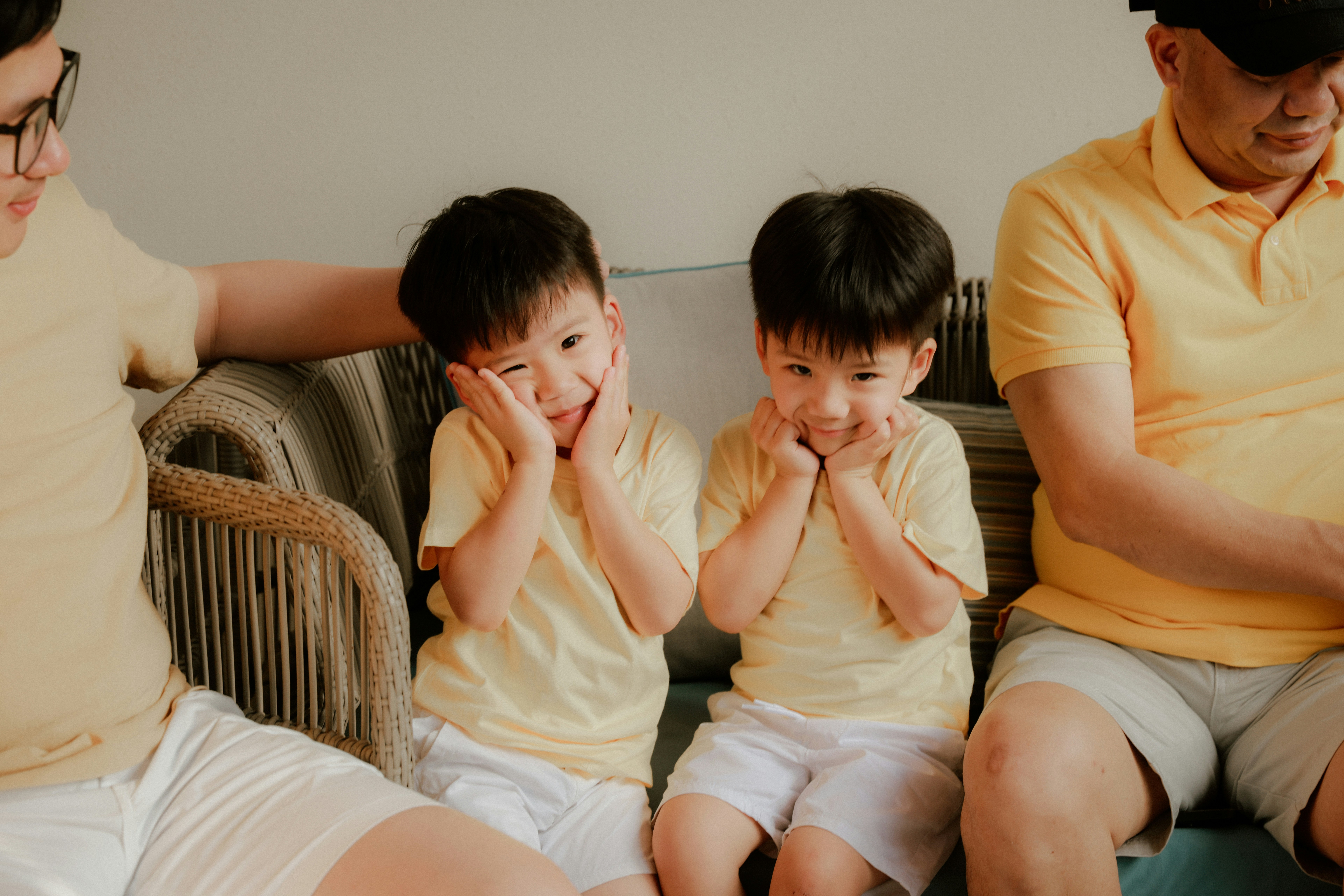 Quiet giggles on a sunlit couch: siblings and adults in a warm family moment