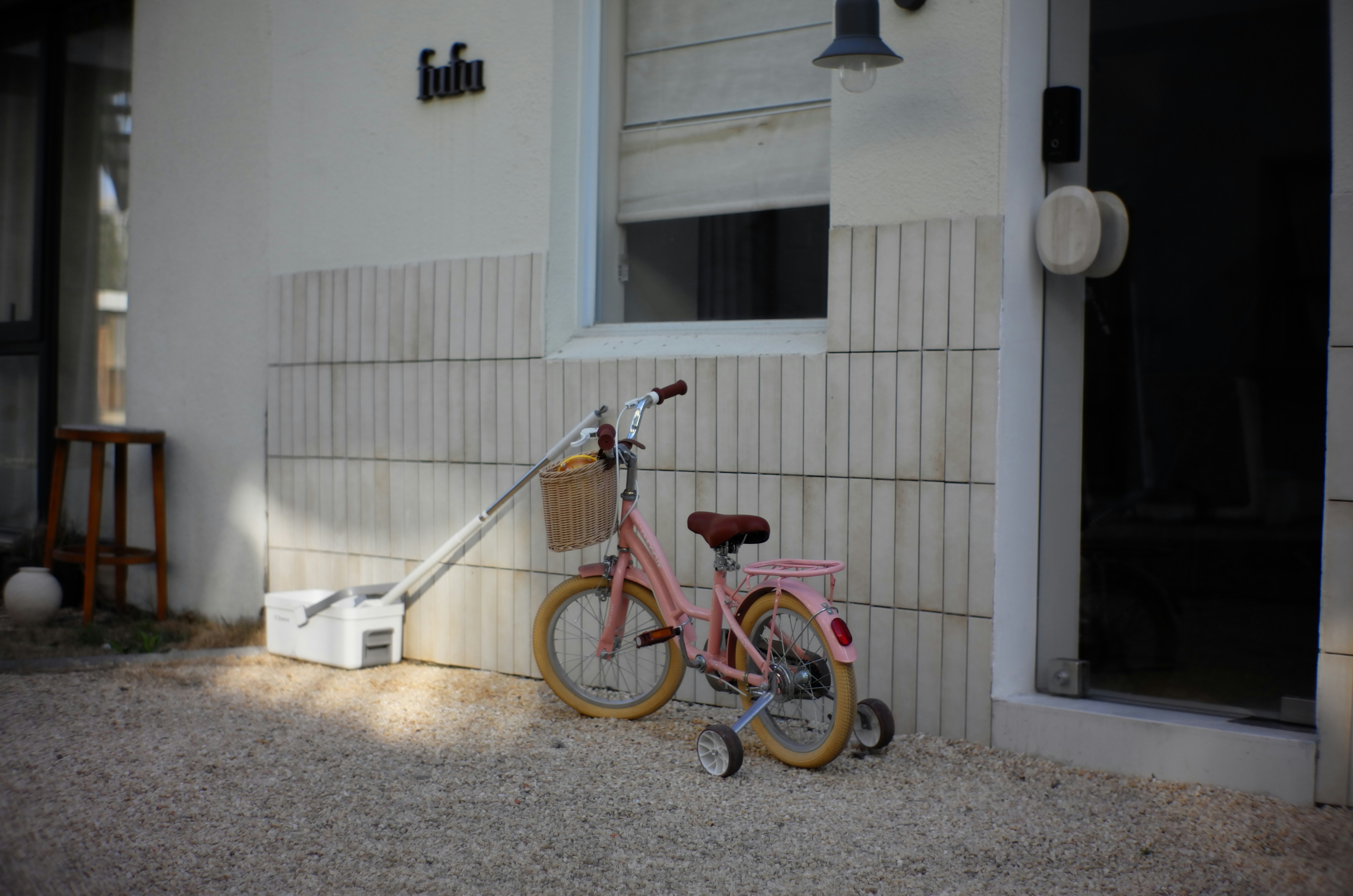 A pink bicycle with training wheels parked outside.