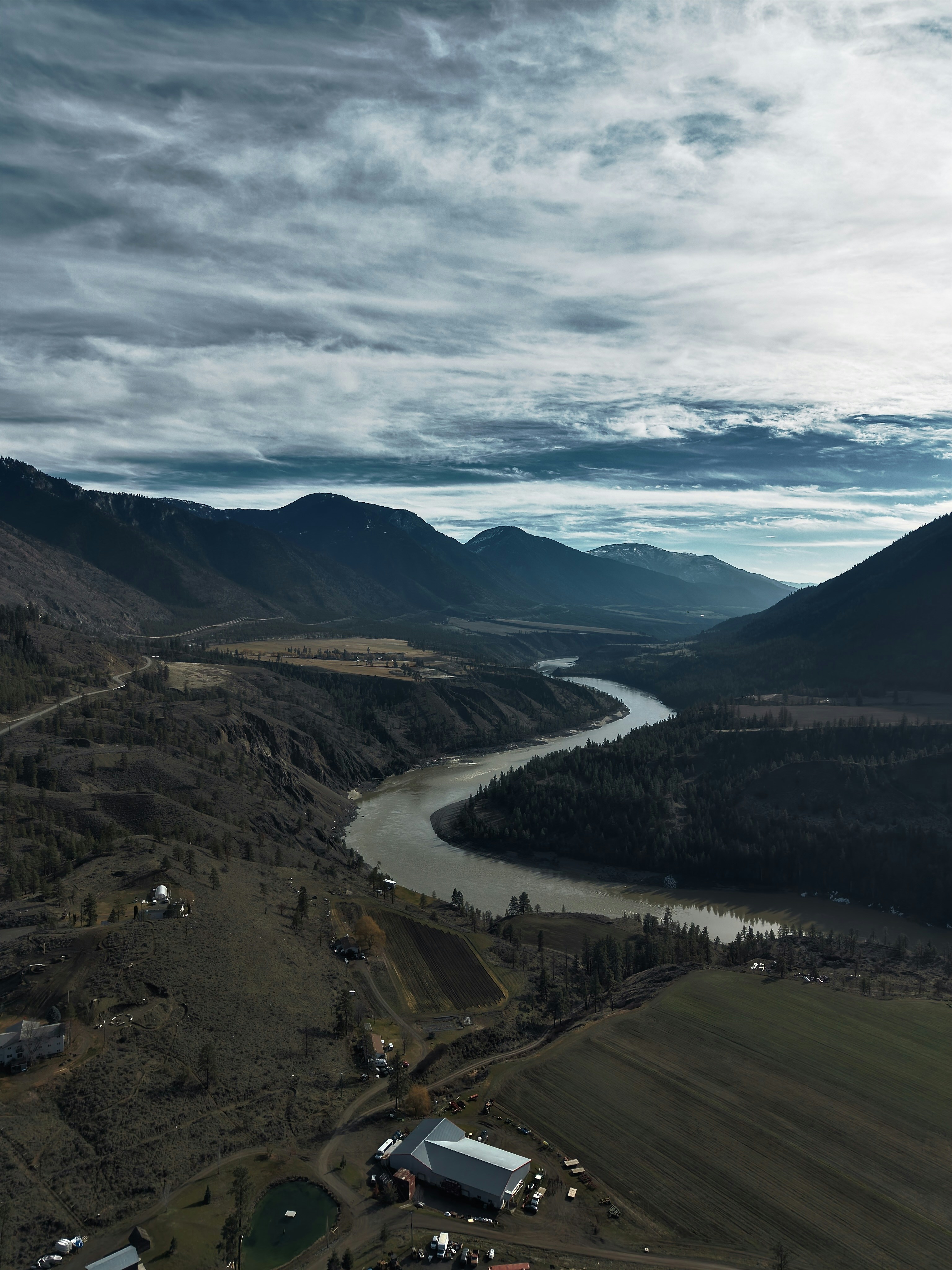 Meandering River Between Folded Mountains Under a Striated Sky