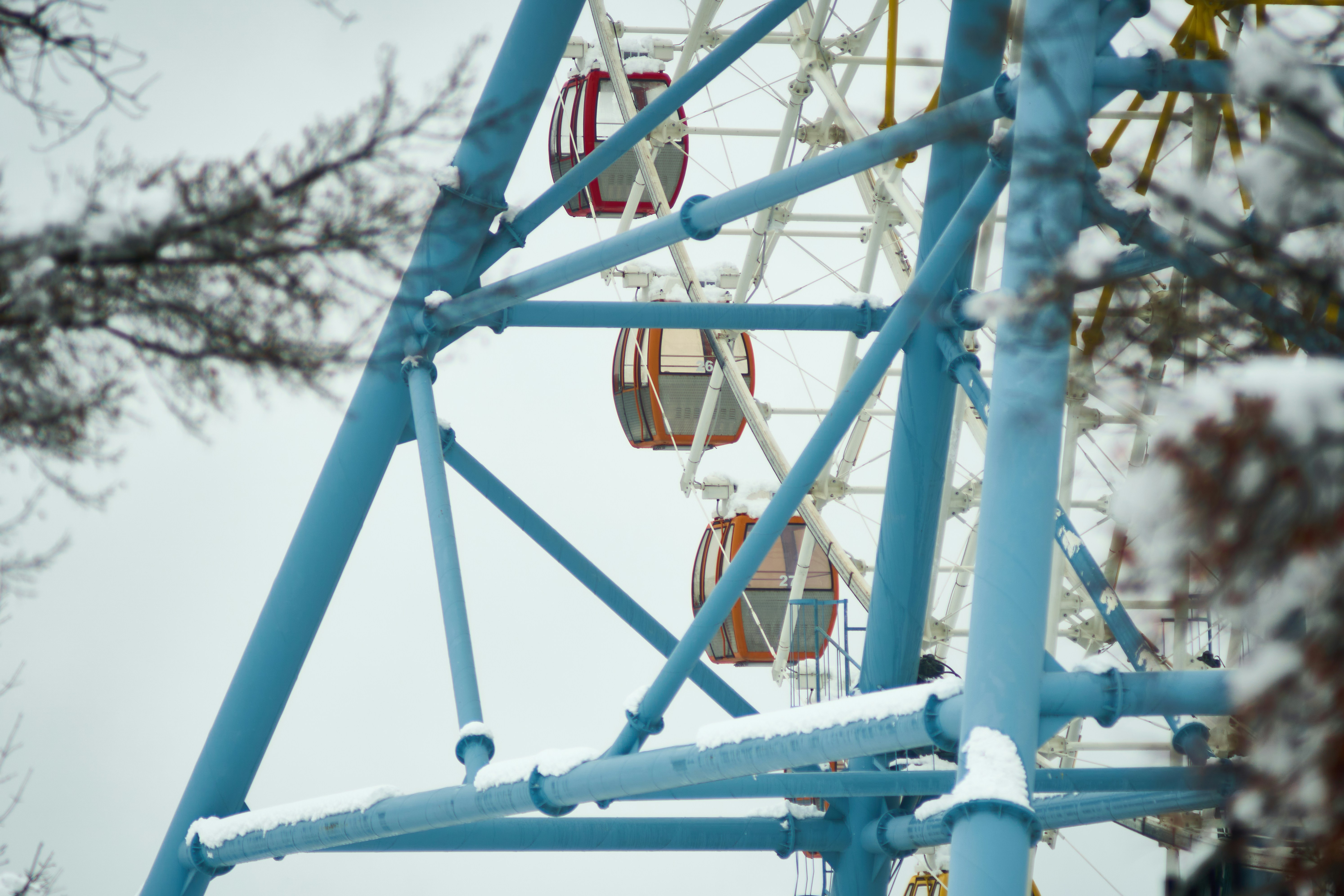 Snow-Capped Framework: A Blue Ferris Wheel Rising Through Winter Silence