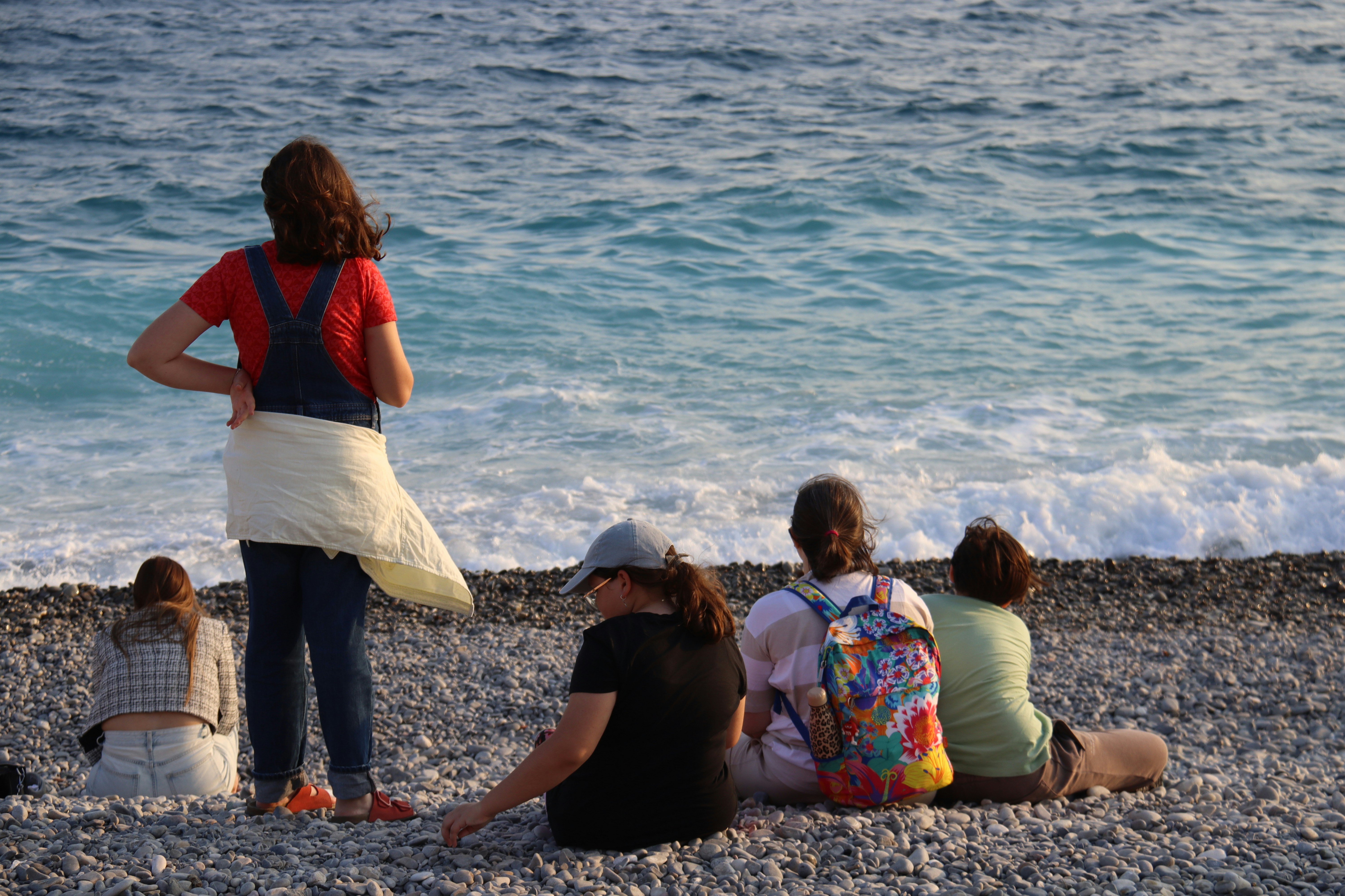 Group of Beachgoers on a Pebble Shore Watch the Wave