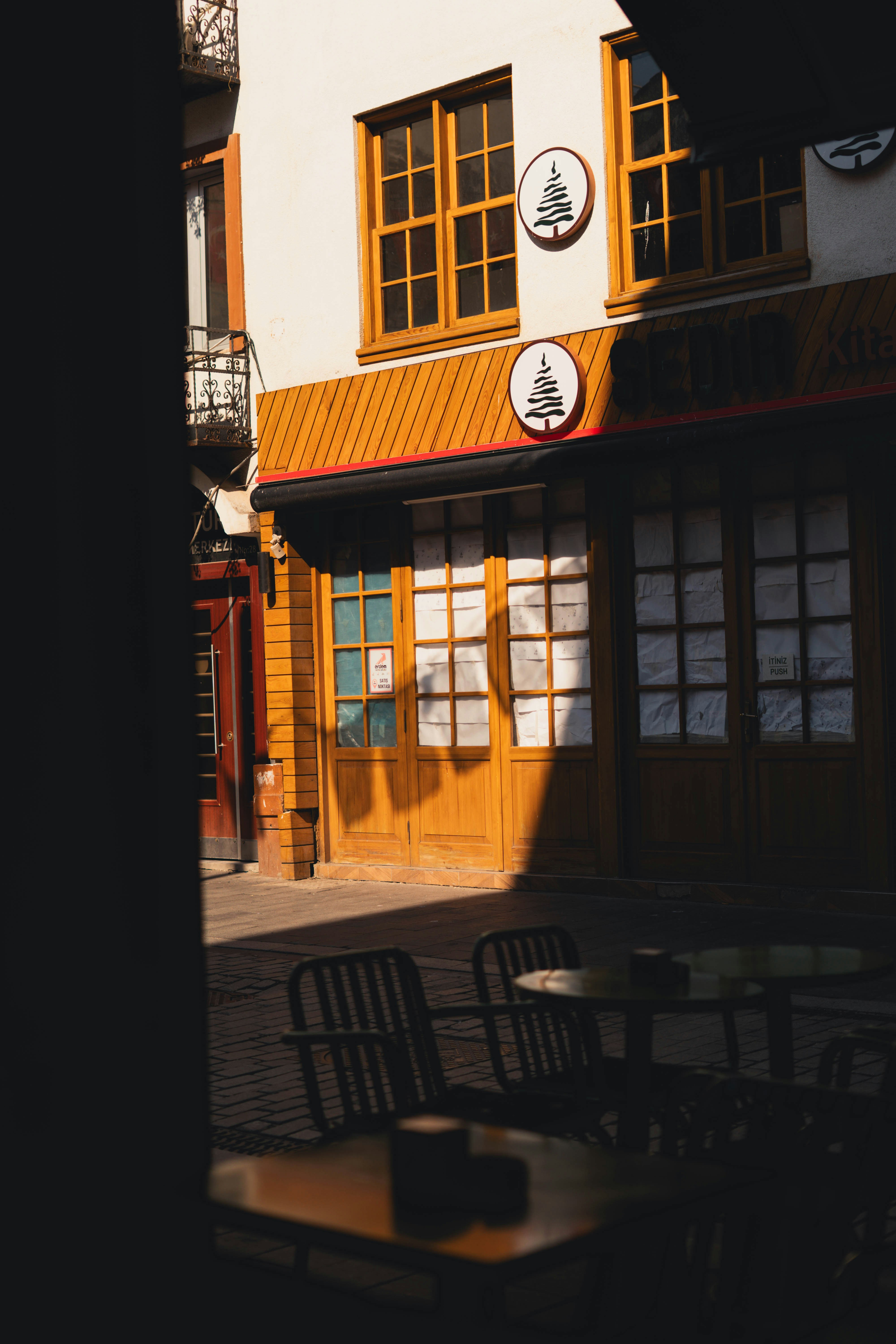 Golden Facade Overhangs: Sunlit Café Terrace in Shadowed Arcade