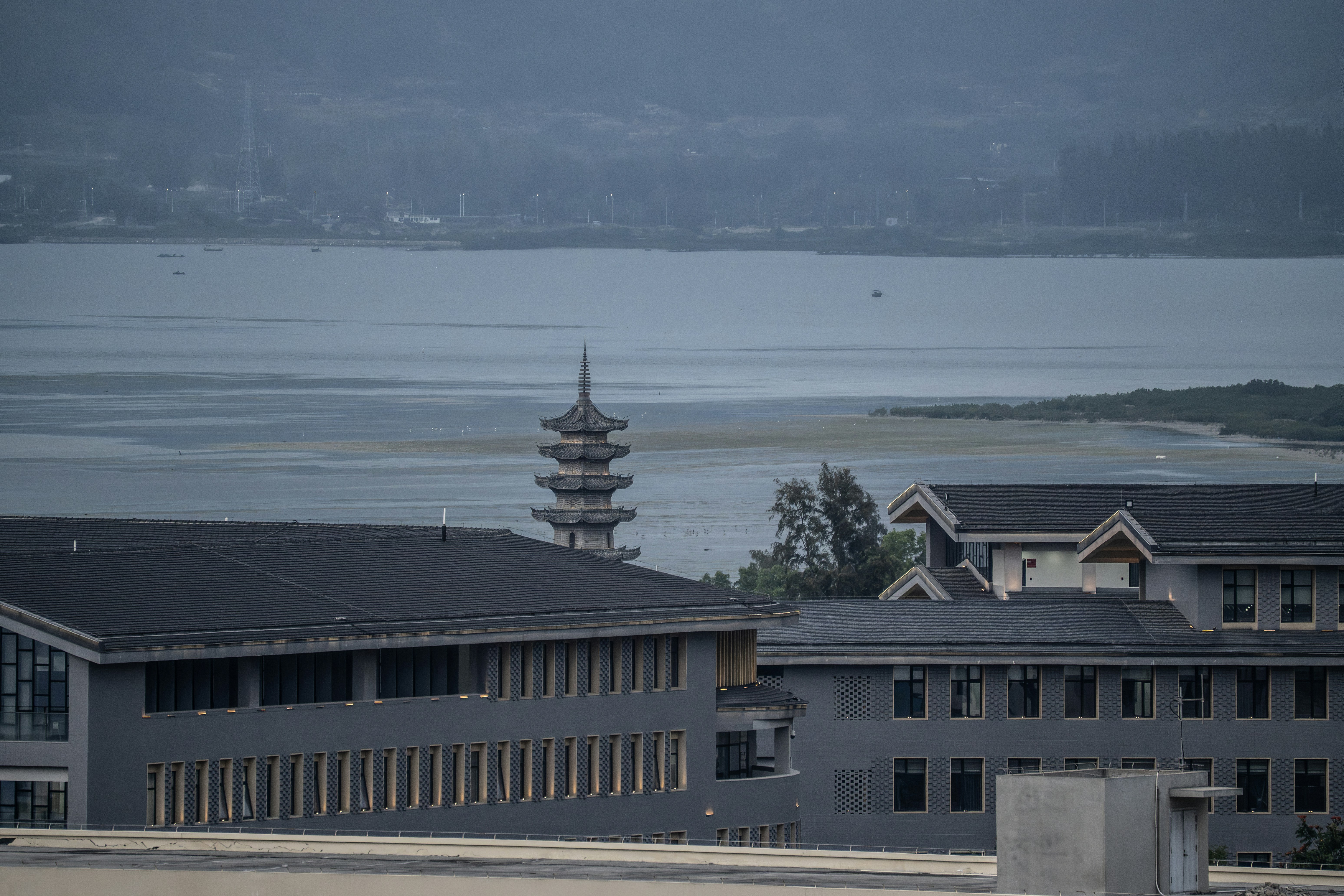 Urban skyline meets tranquil shoreline under a distant pagoda