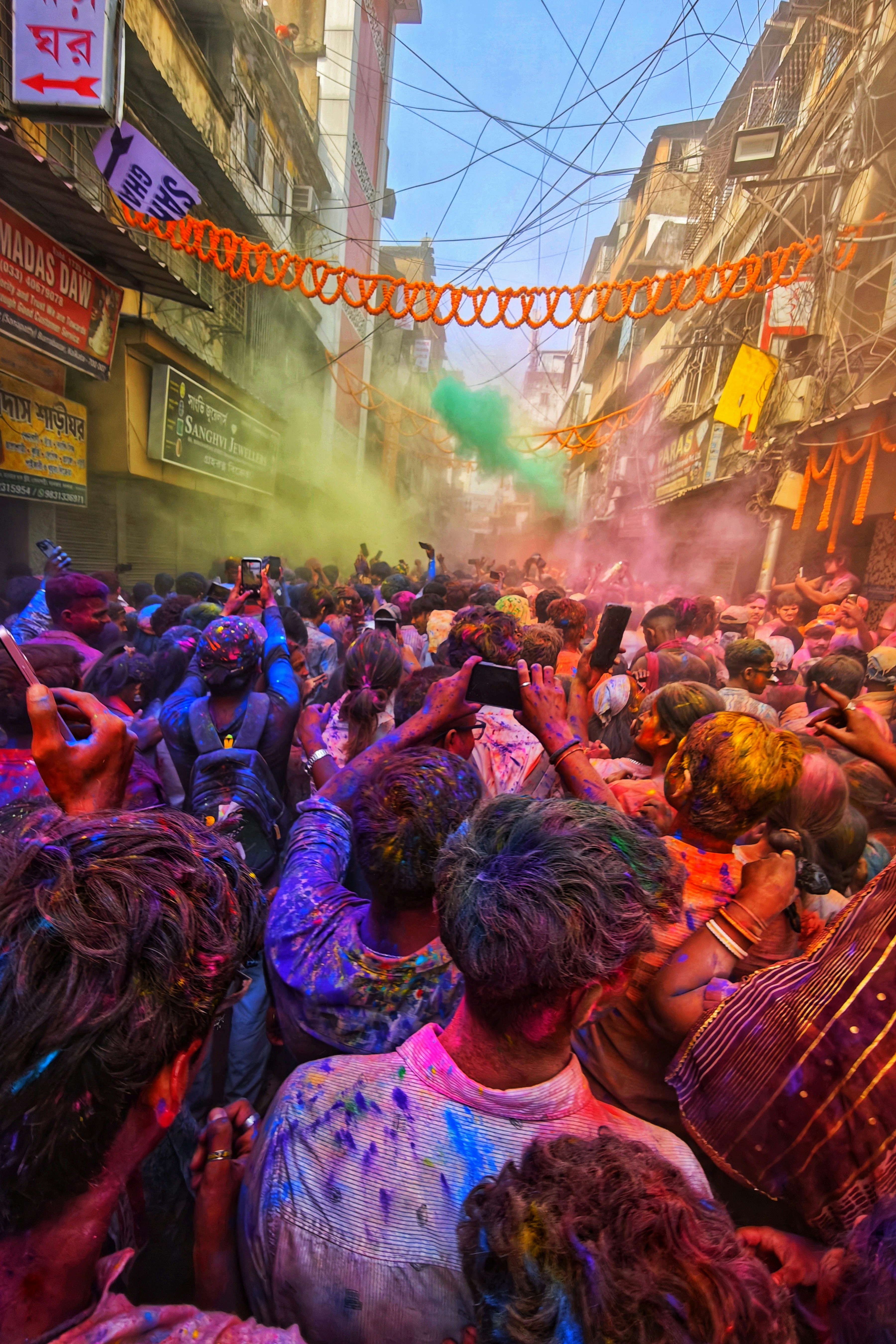 Crowd celebrating holi with colored powder in street