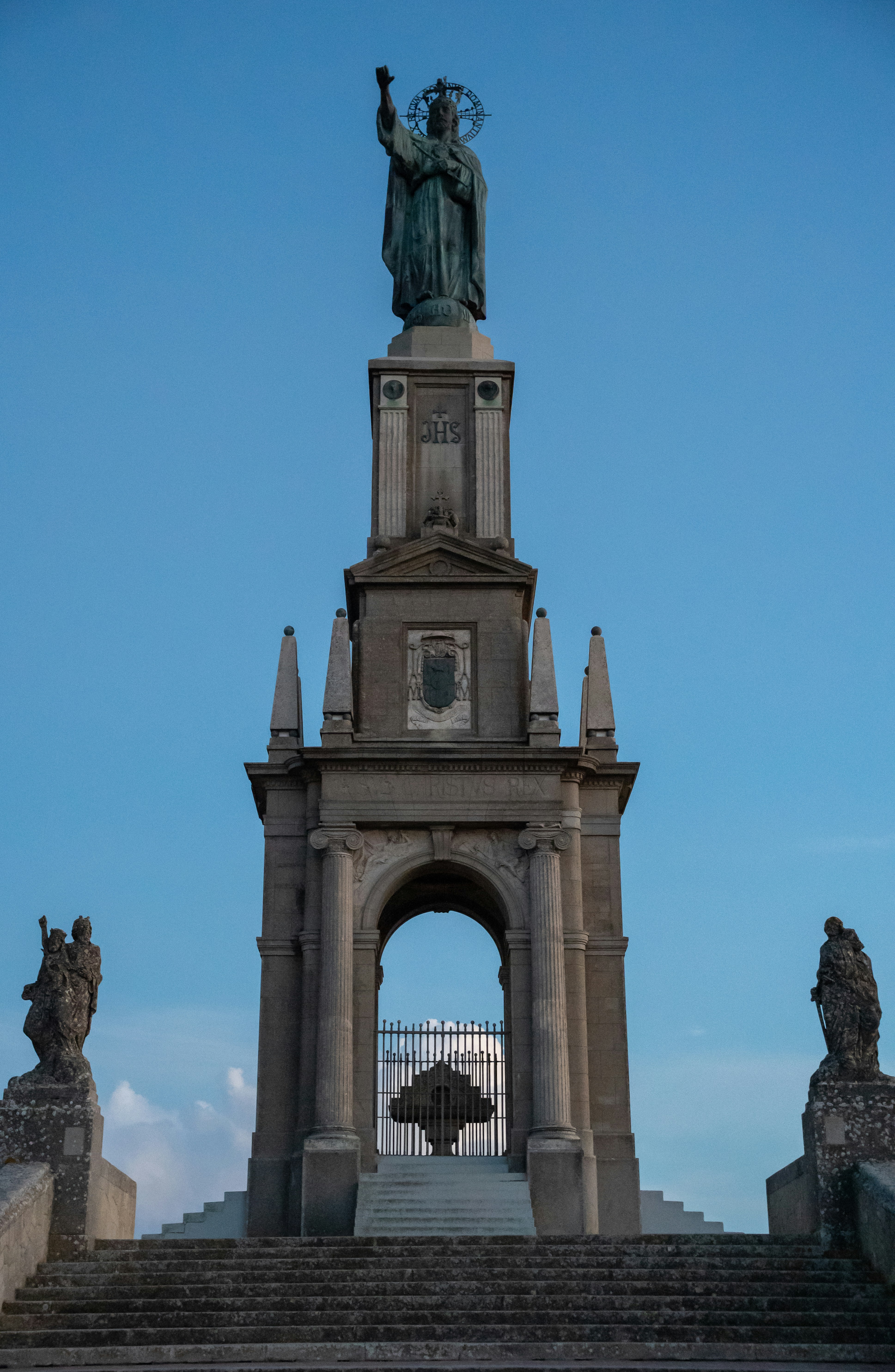 Elevated Guardian: Portrait of a Monumental Statue Framing a Stairway to the Gate