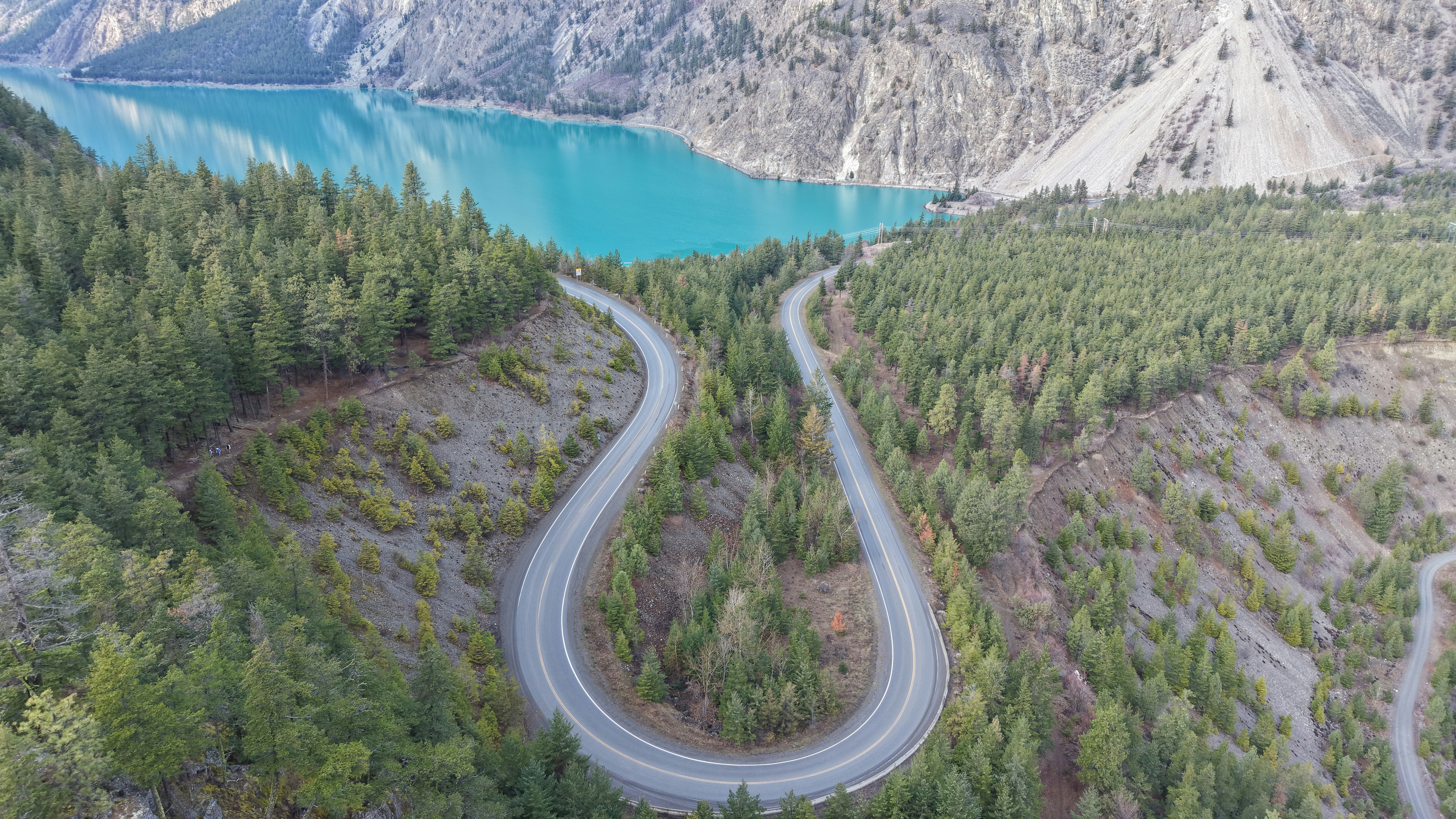 Winding mountain road beside a turquoise lake