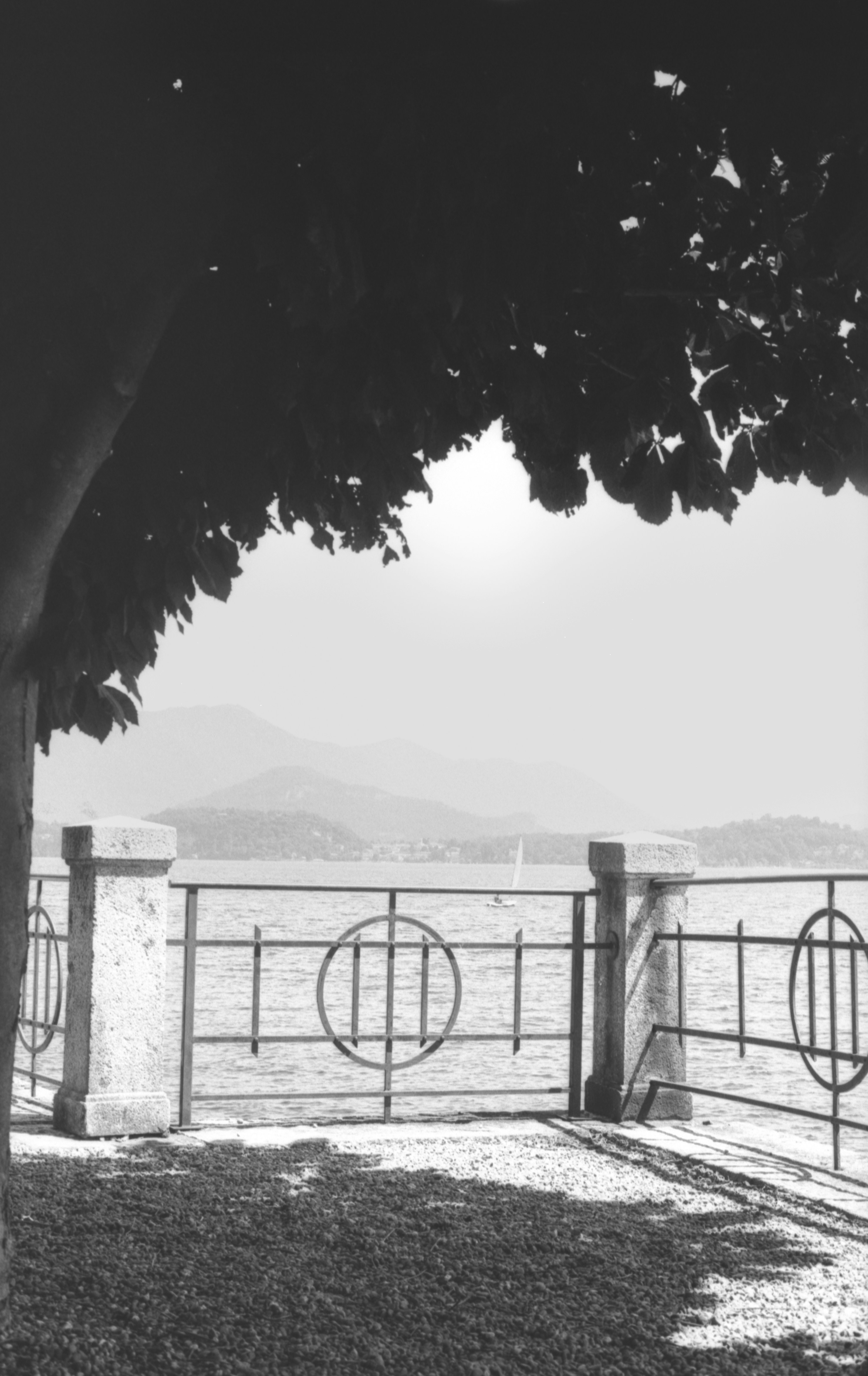 Waterfront promenade with ornate railing and distant hills.