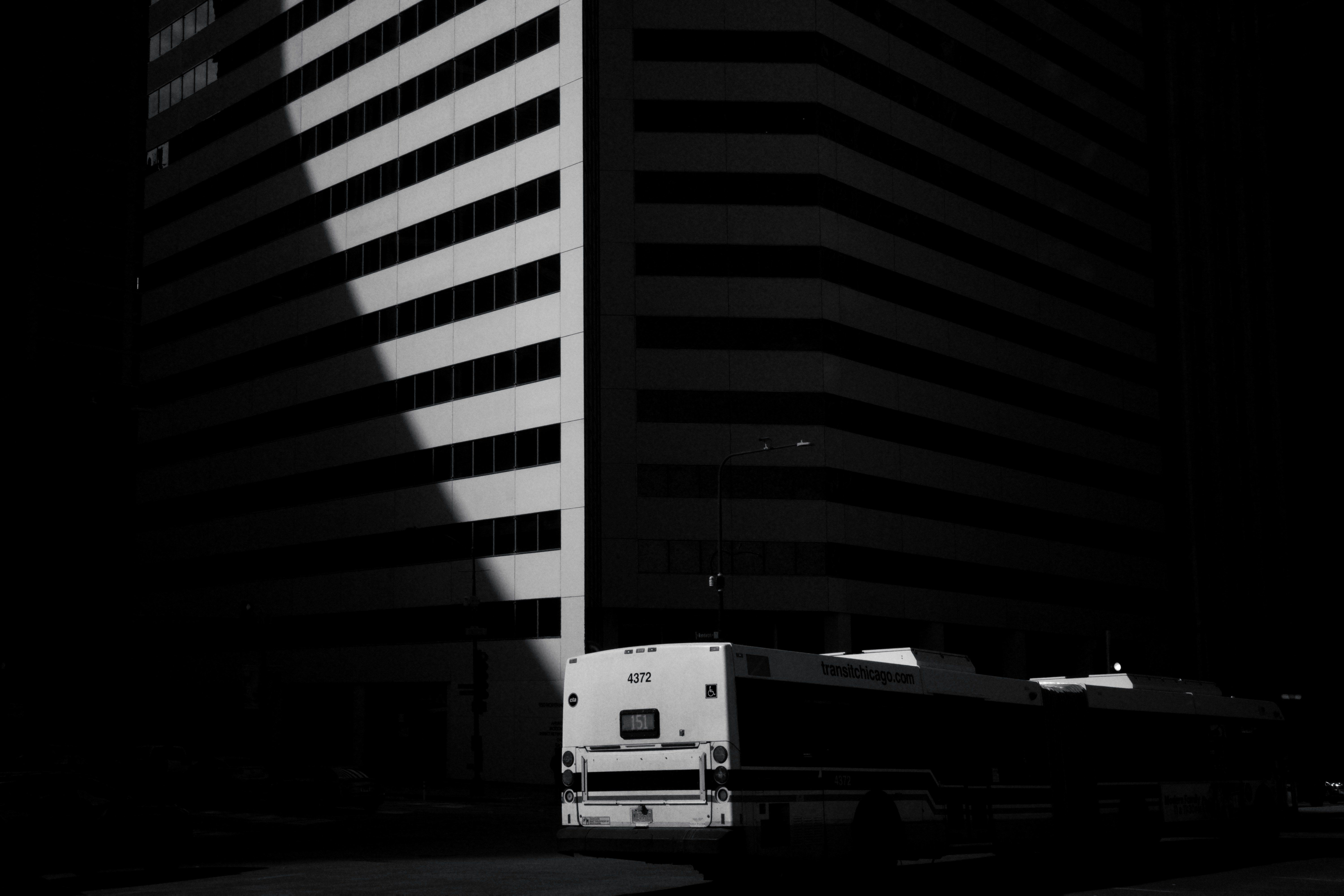 Shadowed Urban Mono: A Bus Under the Skyscraper Rim