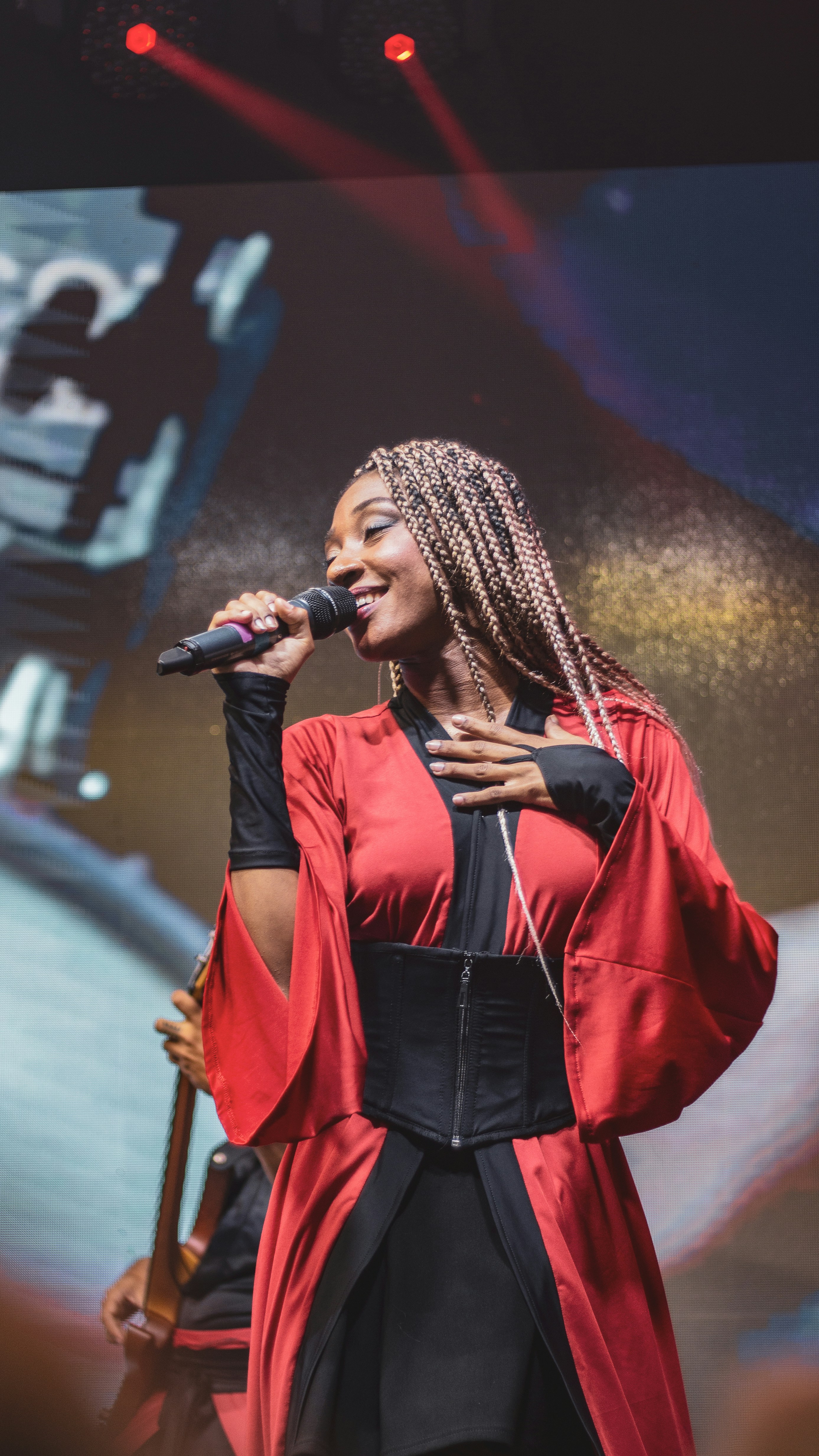 Vibrant Vocalist in Crimson Robe Under Stage Lights