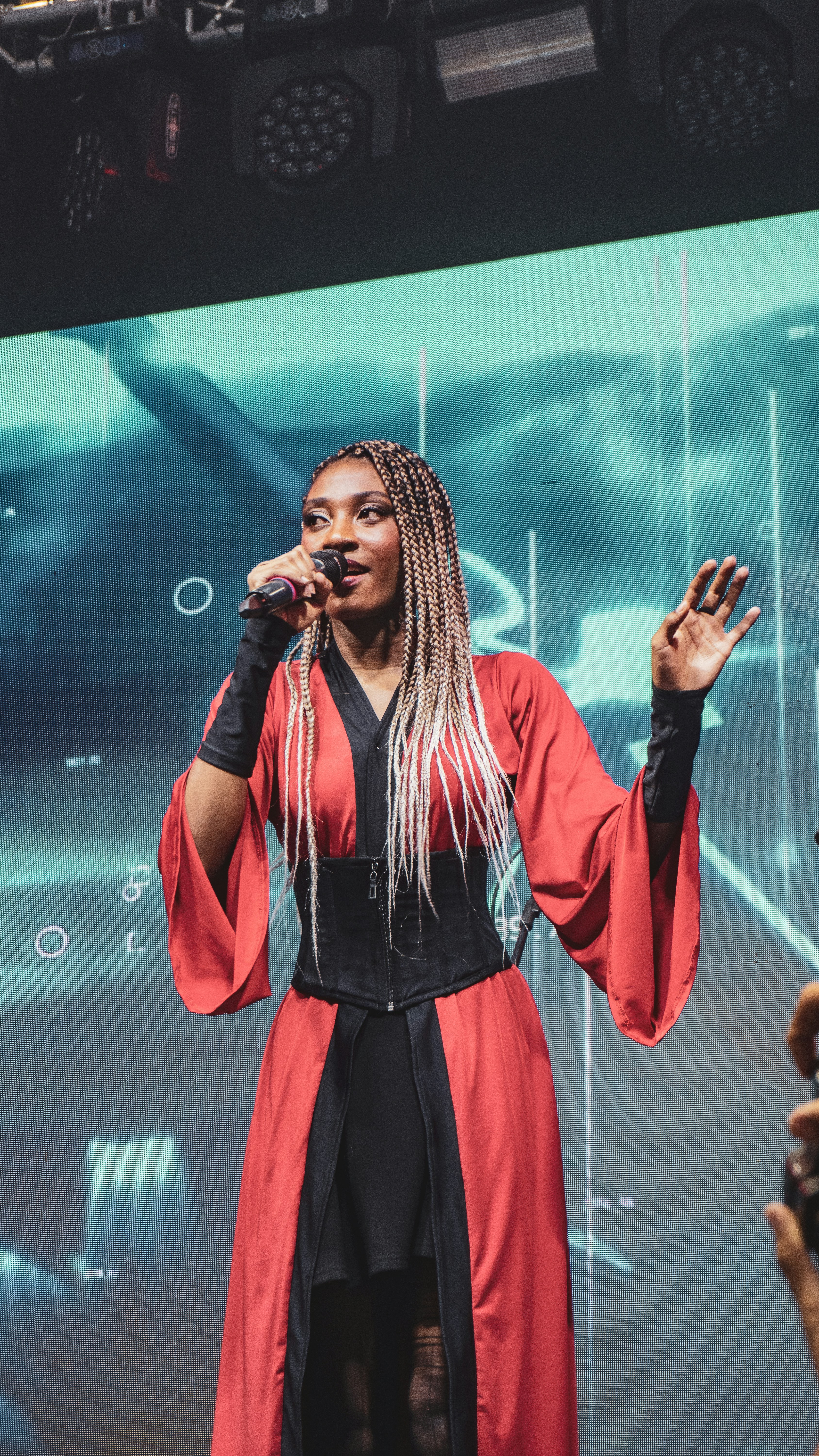 Red-robed vocalist in mid-performance under stage lights