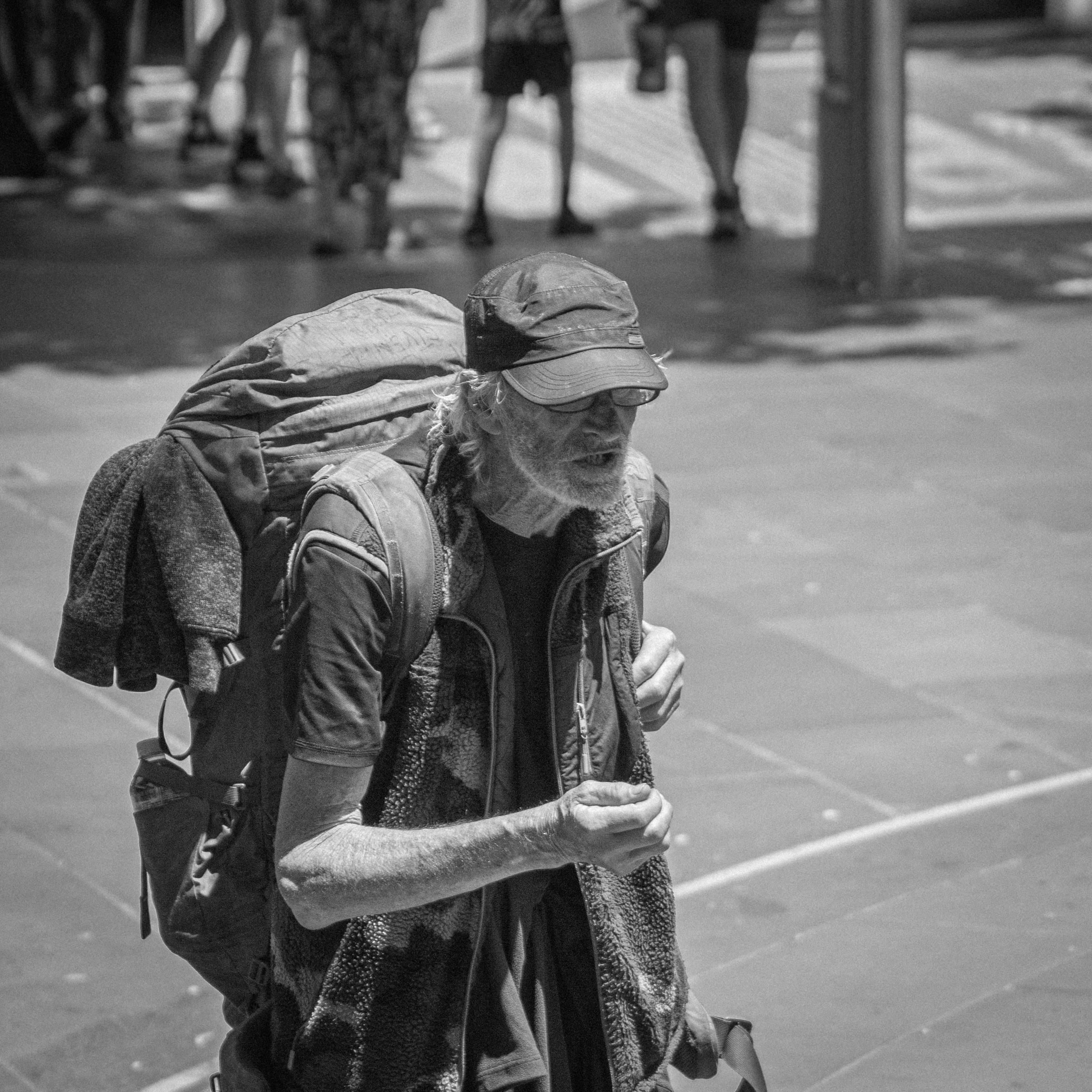 A Weathered Traveler Steps Through the City Footpath