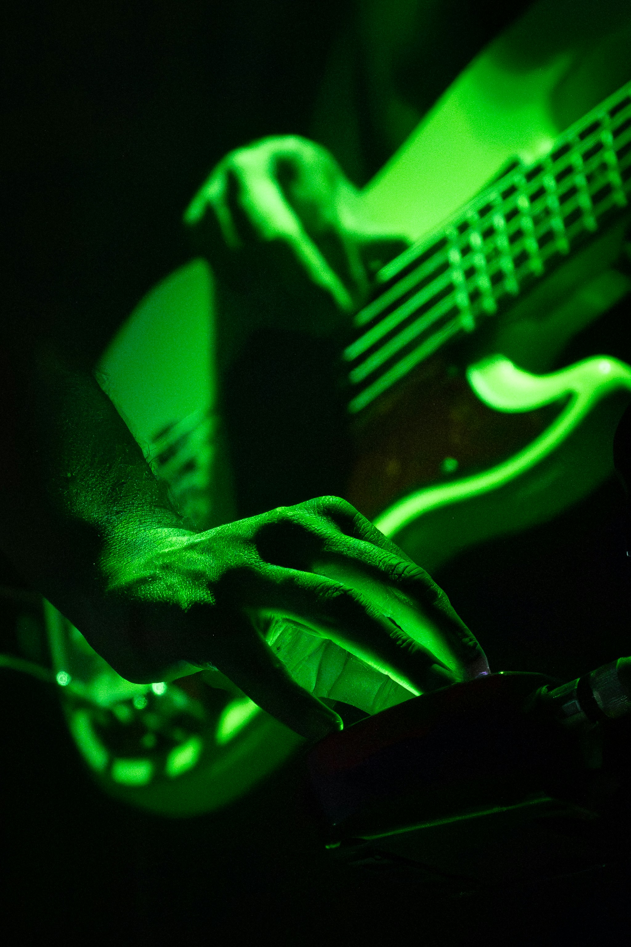 Green Light, Steady Hands: A Guitarist's Shadowed Hands in Concert Glow
