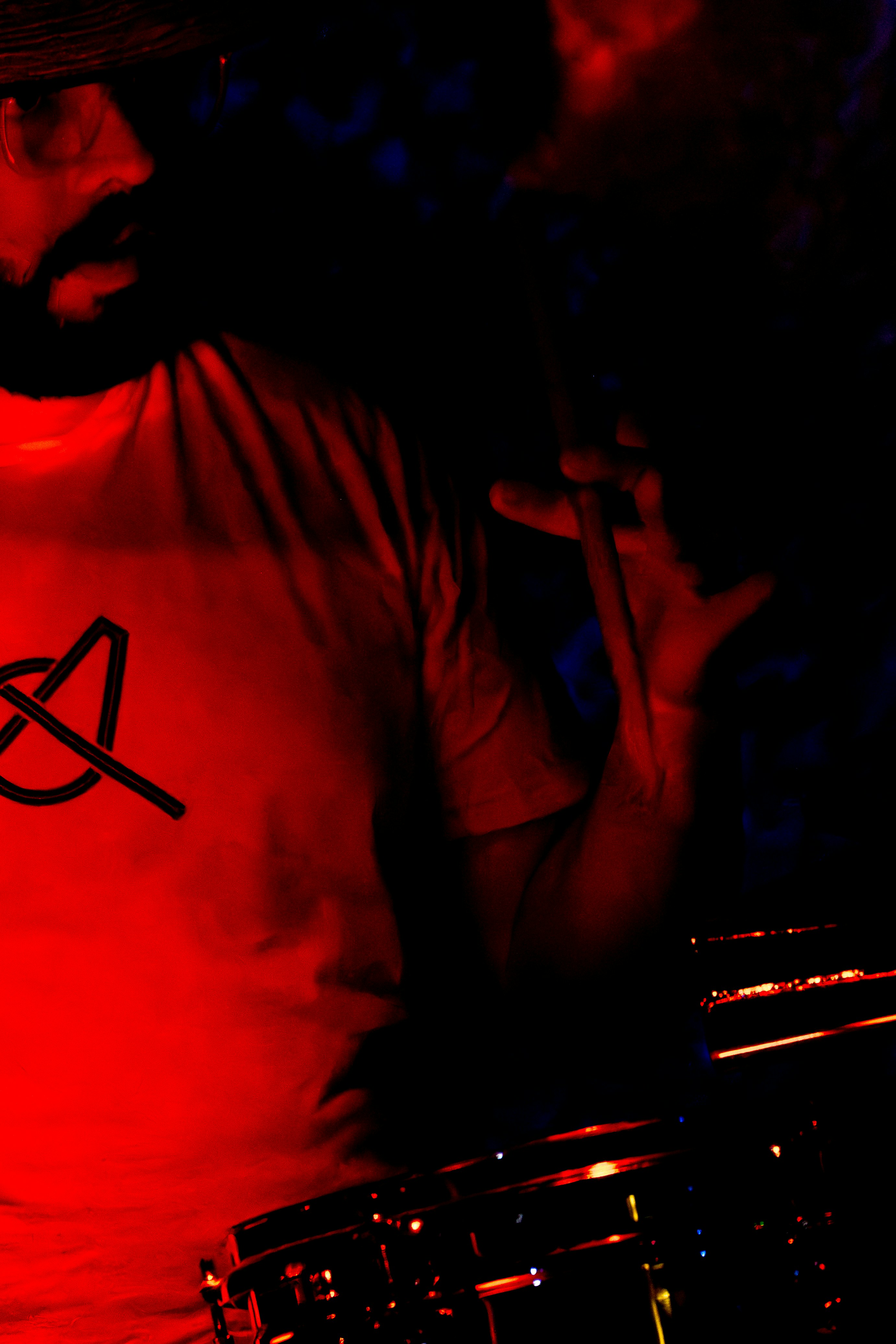 Red-lit Drummer’s Face Found in Shadows
