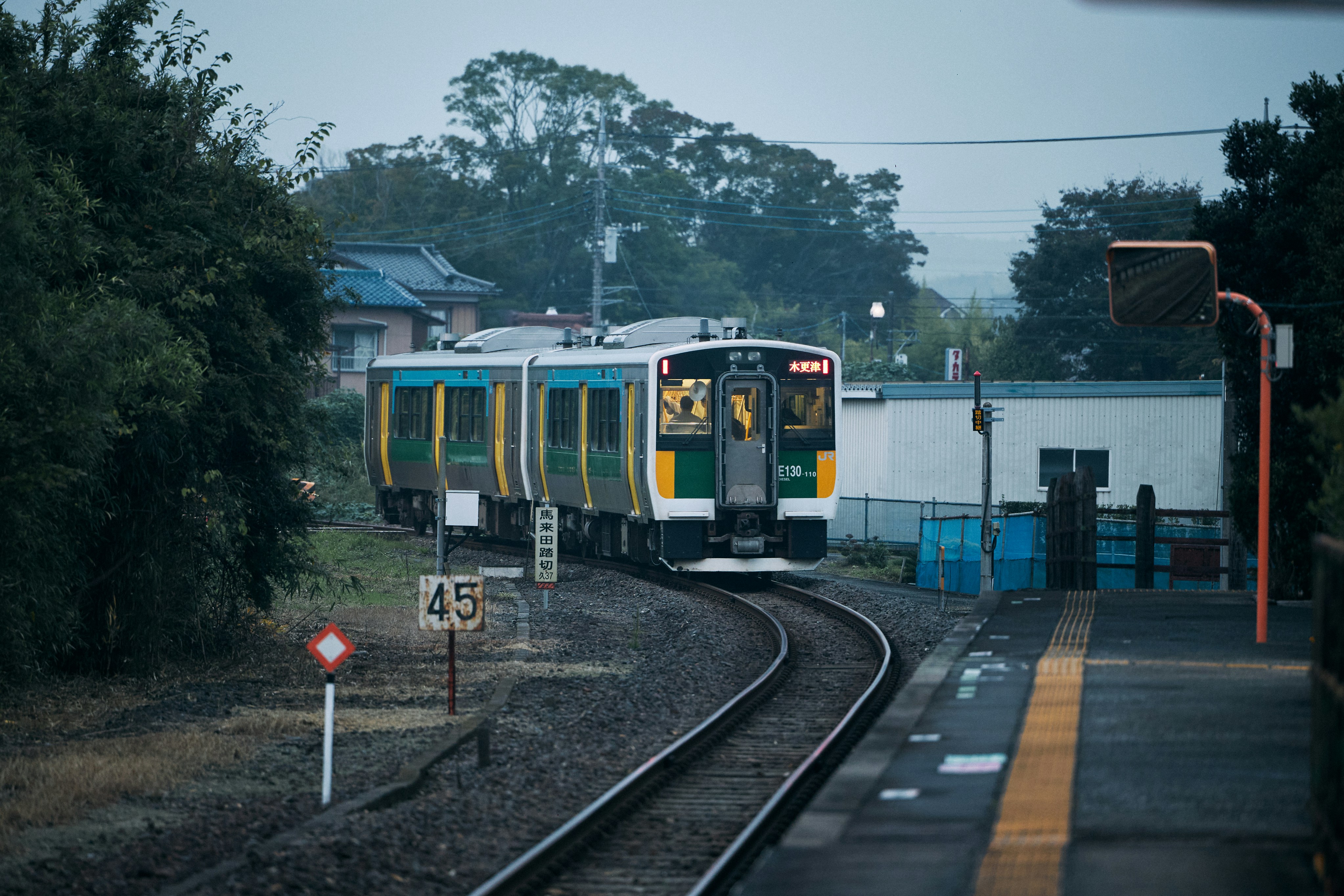 Green-and-White Commuter Carriage Rounding the Rural Curve